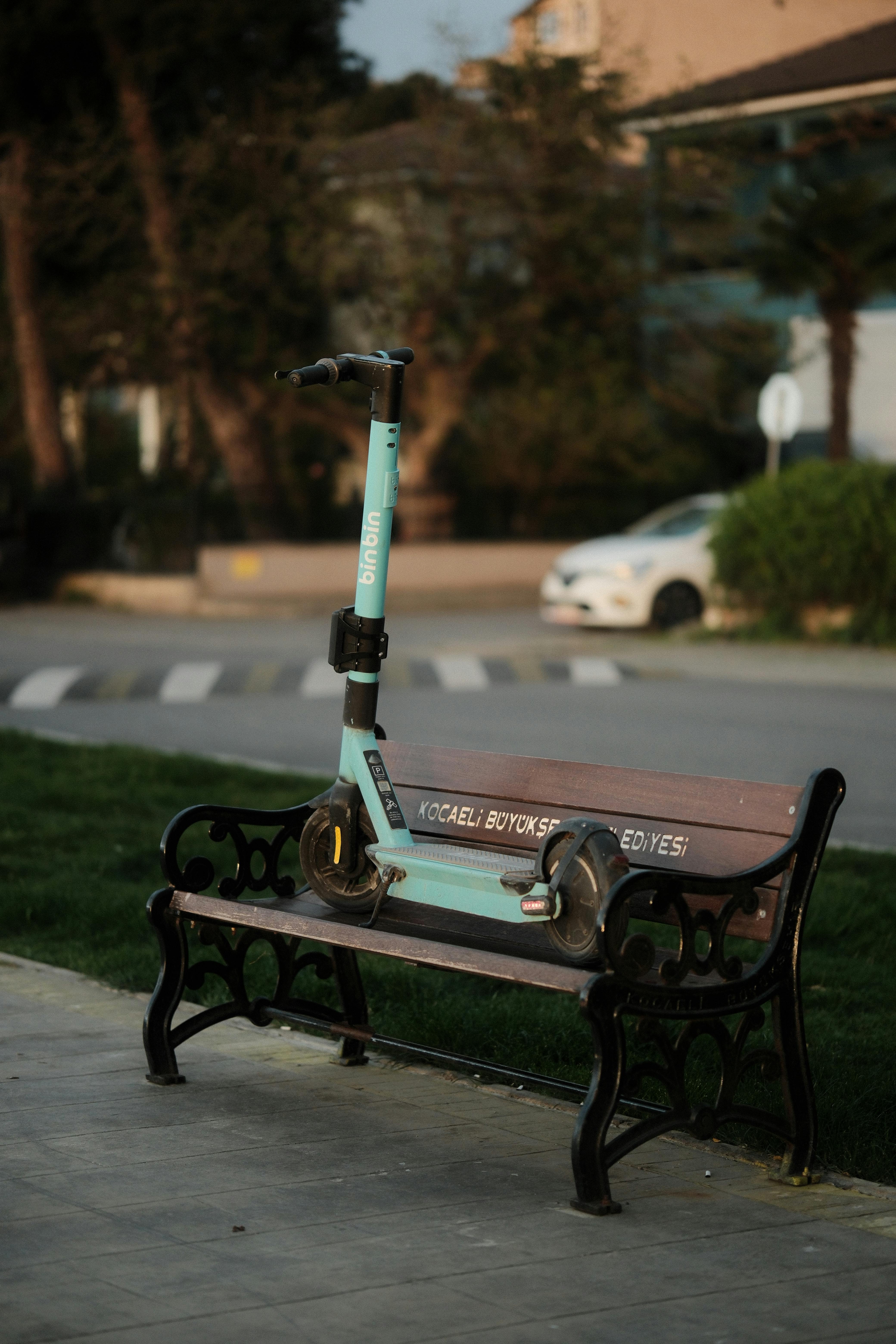 Turquoise Electric Scooter Resting on Park Bench · Free Stock Photo