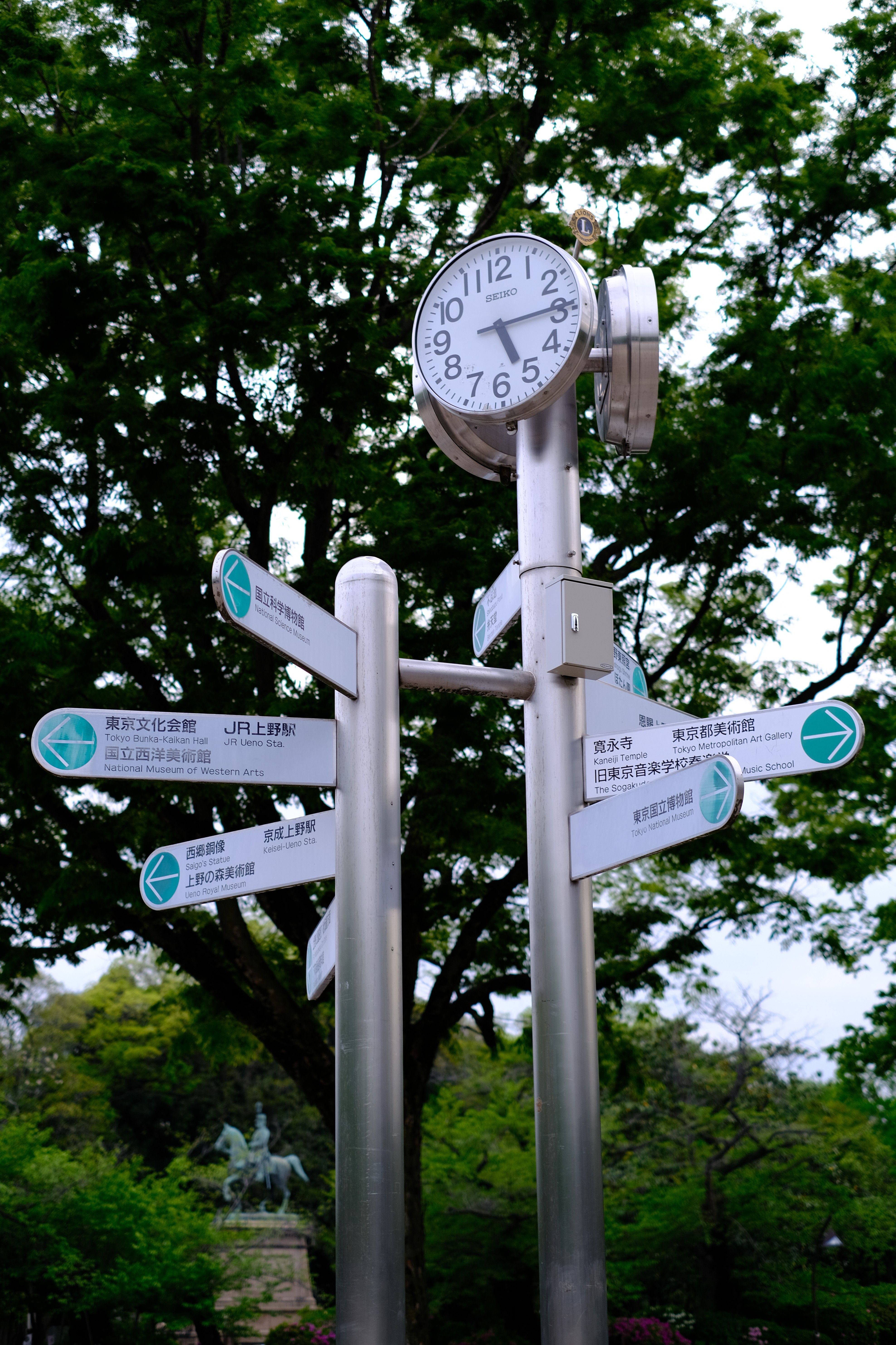 Urban Clock and Signpost in Lush Park Setting · Free Stock Photo