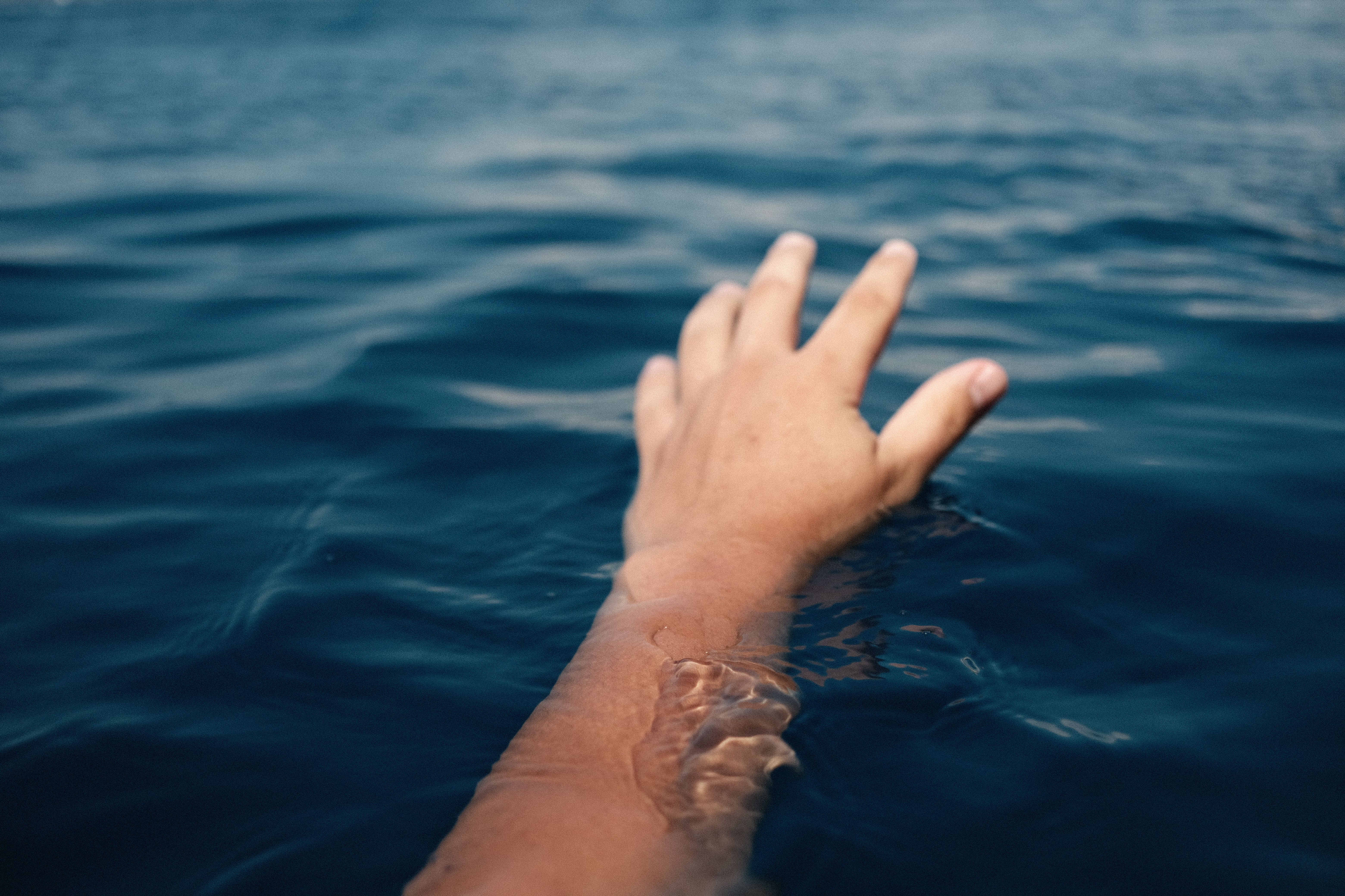 Outstretched Hand Reaching Over Blue Ocean Water · Free Stock Photo