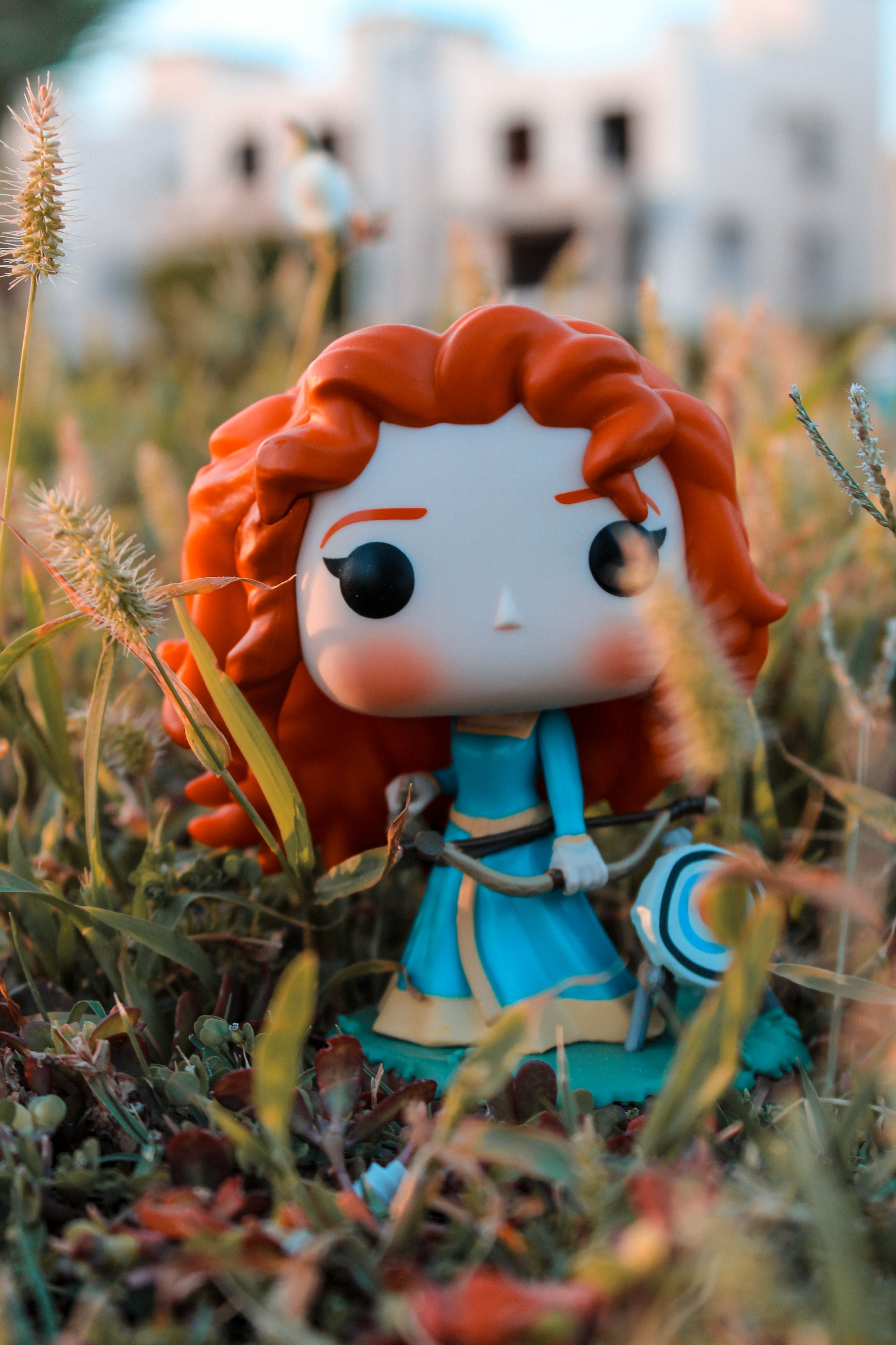 Red-haired Toy Figure in Grassy Field · Free Stock Photo