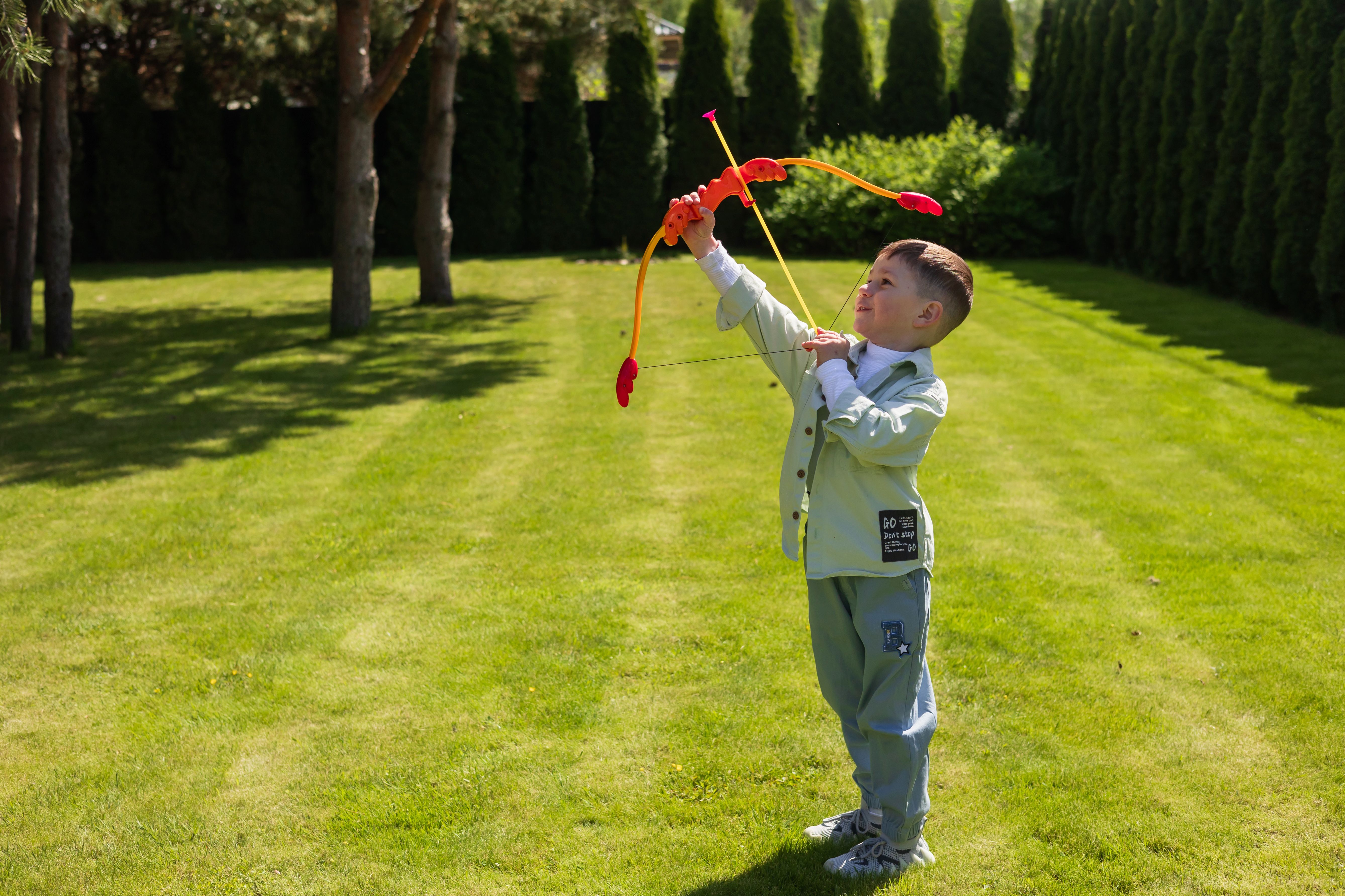 Boy Playing with Toy Bow and Arrow in Garden · Free Stock Photo