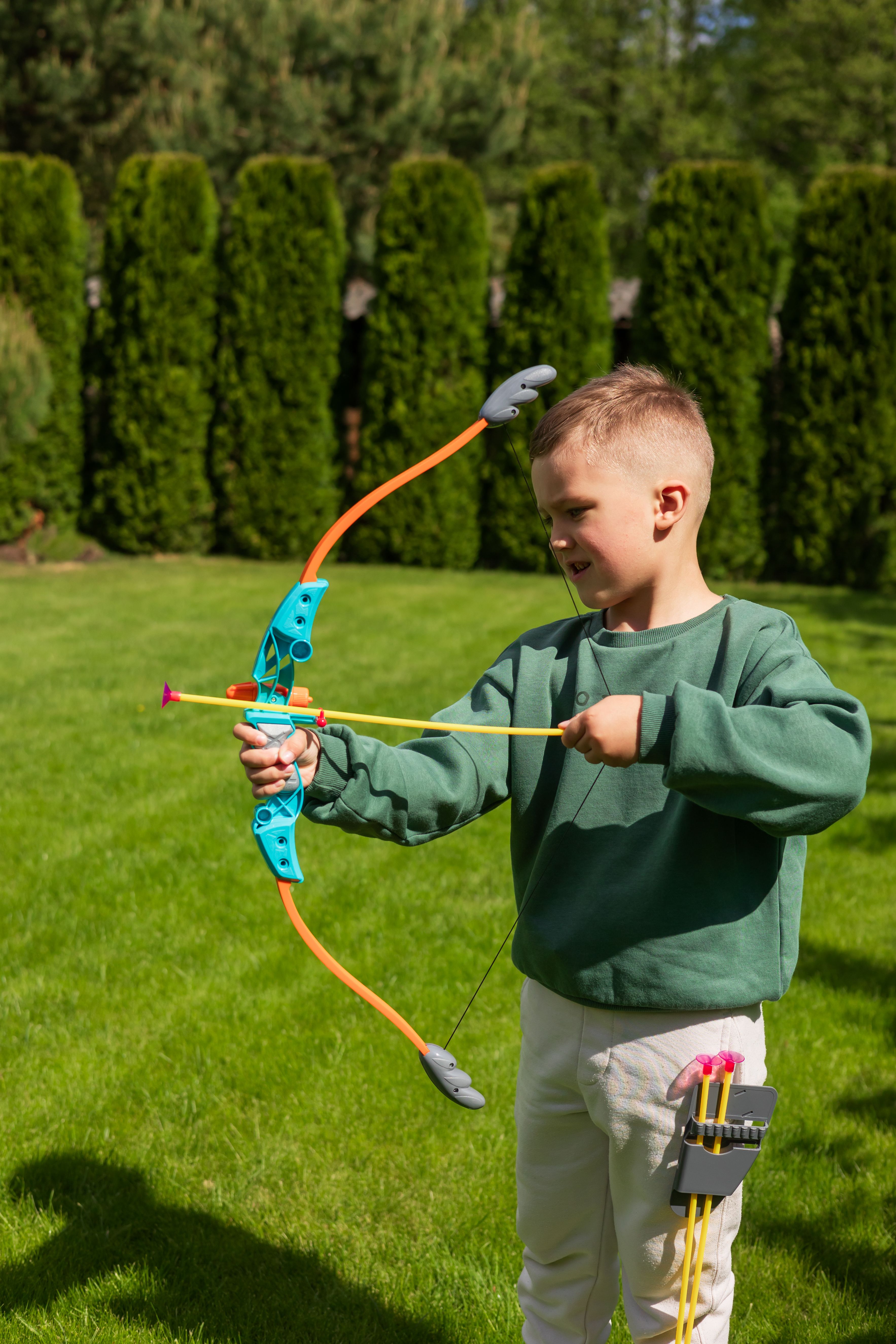 Child practicing archery in a sunny garden · Free Stock Photo