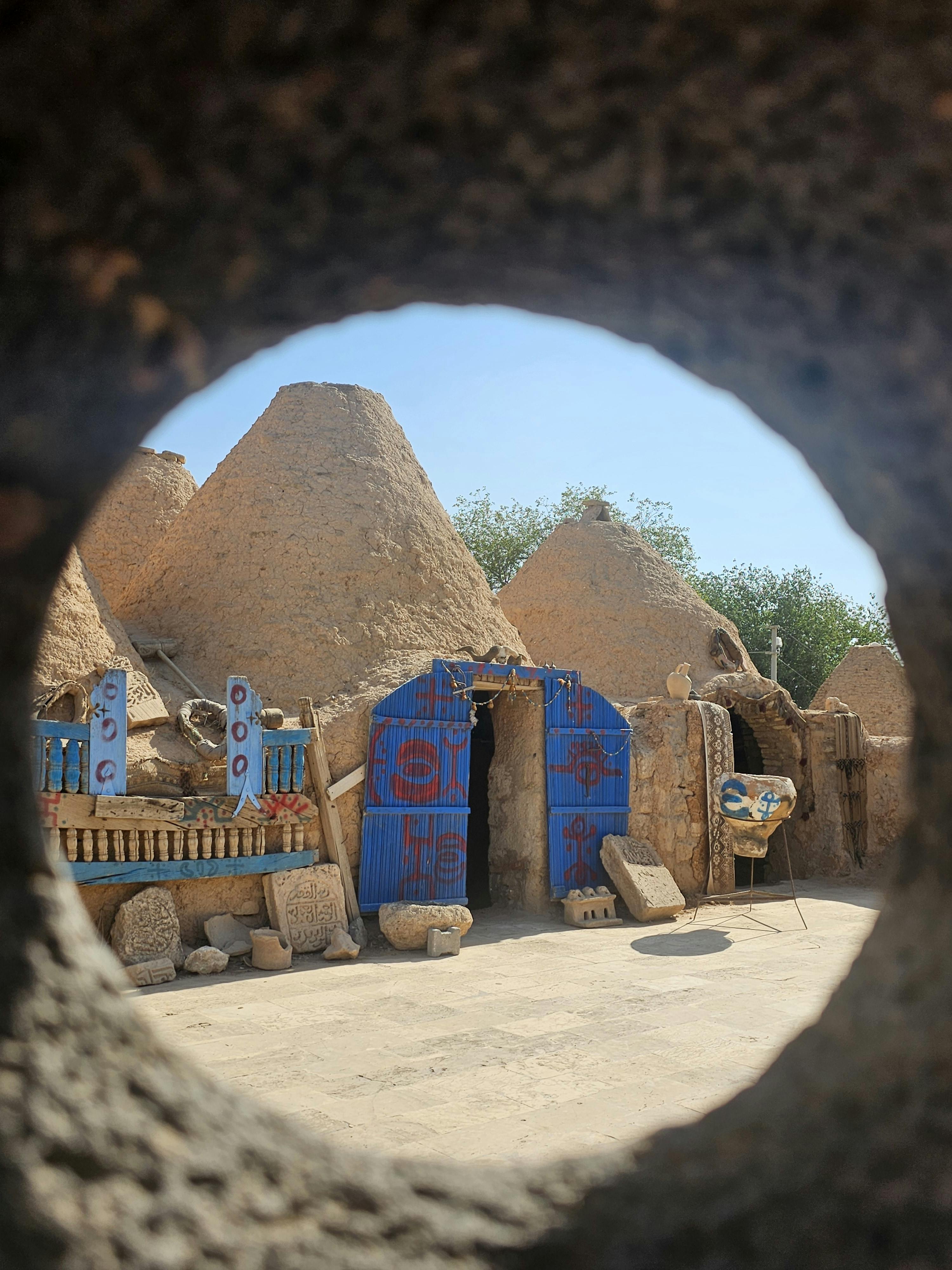 Traditional Mud Brick Conical Houses through Stone Arch · Free Stock Photo