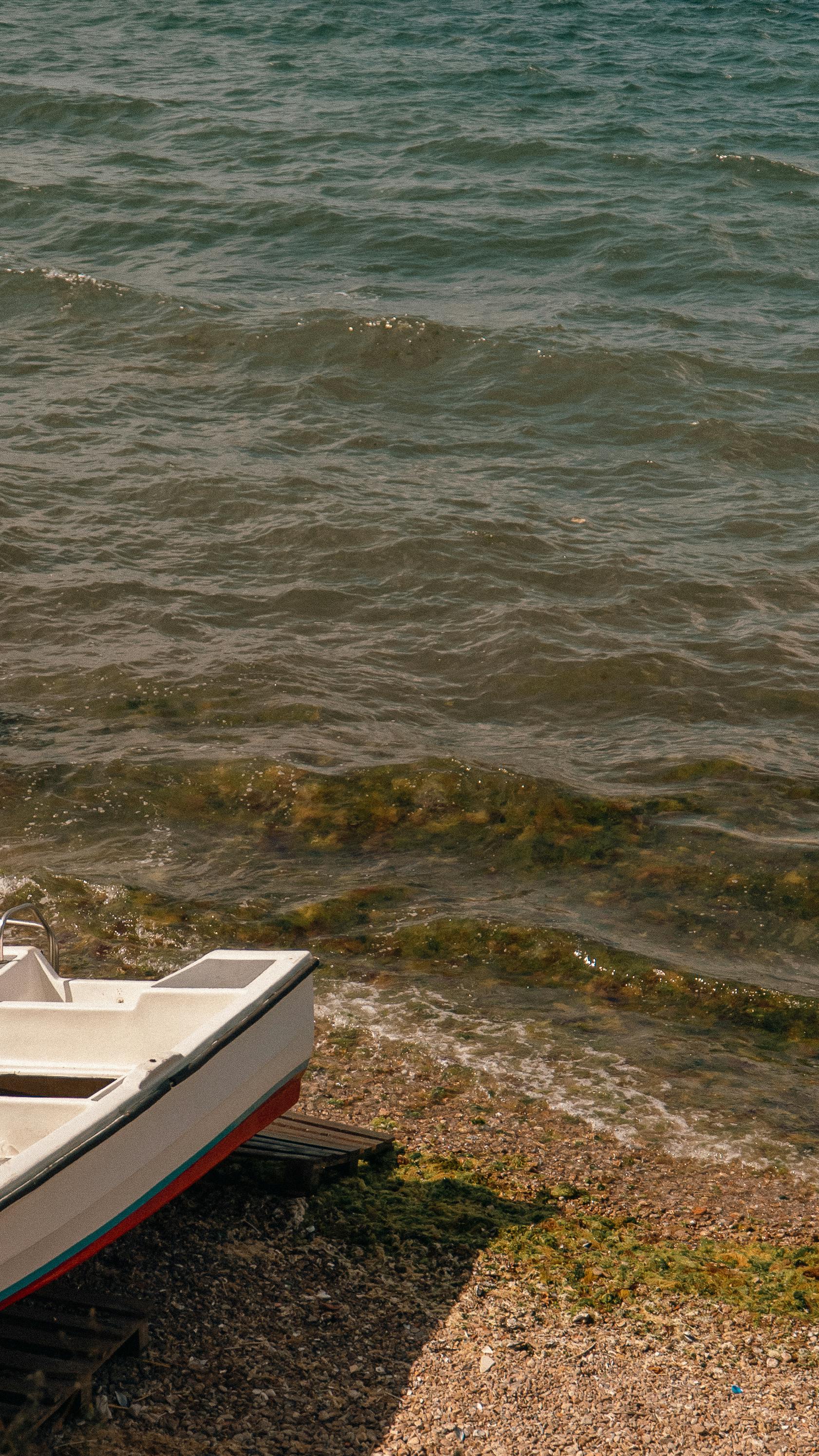 Serene Beachfront with Rowboat on Shore · Free Stock Photo