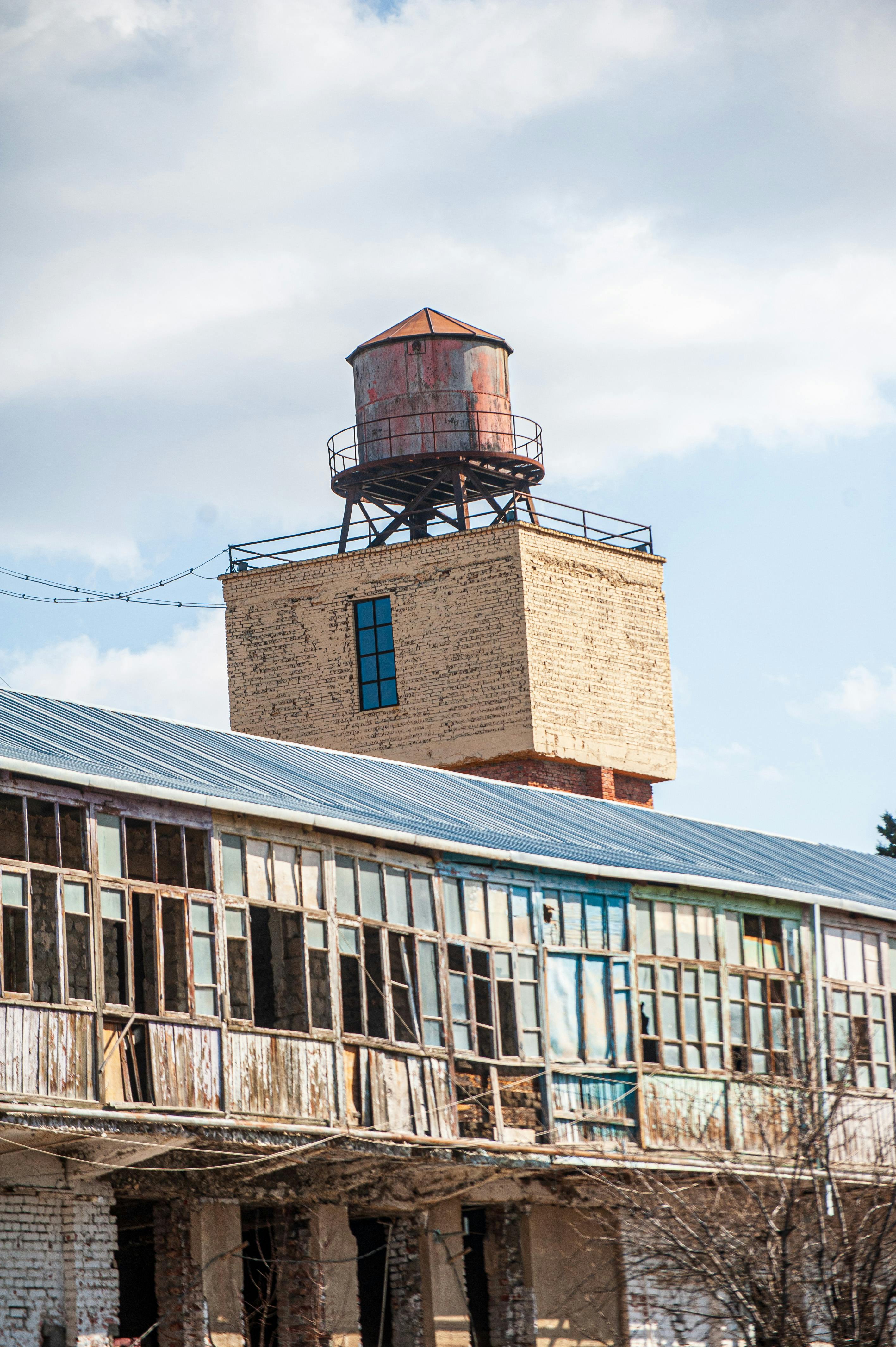 Rustic Water Tower on Industrial Building · Free Stock Photo