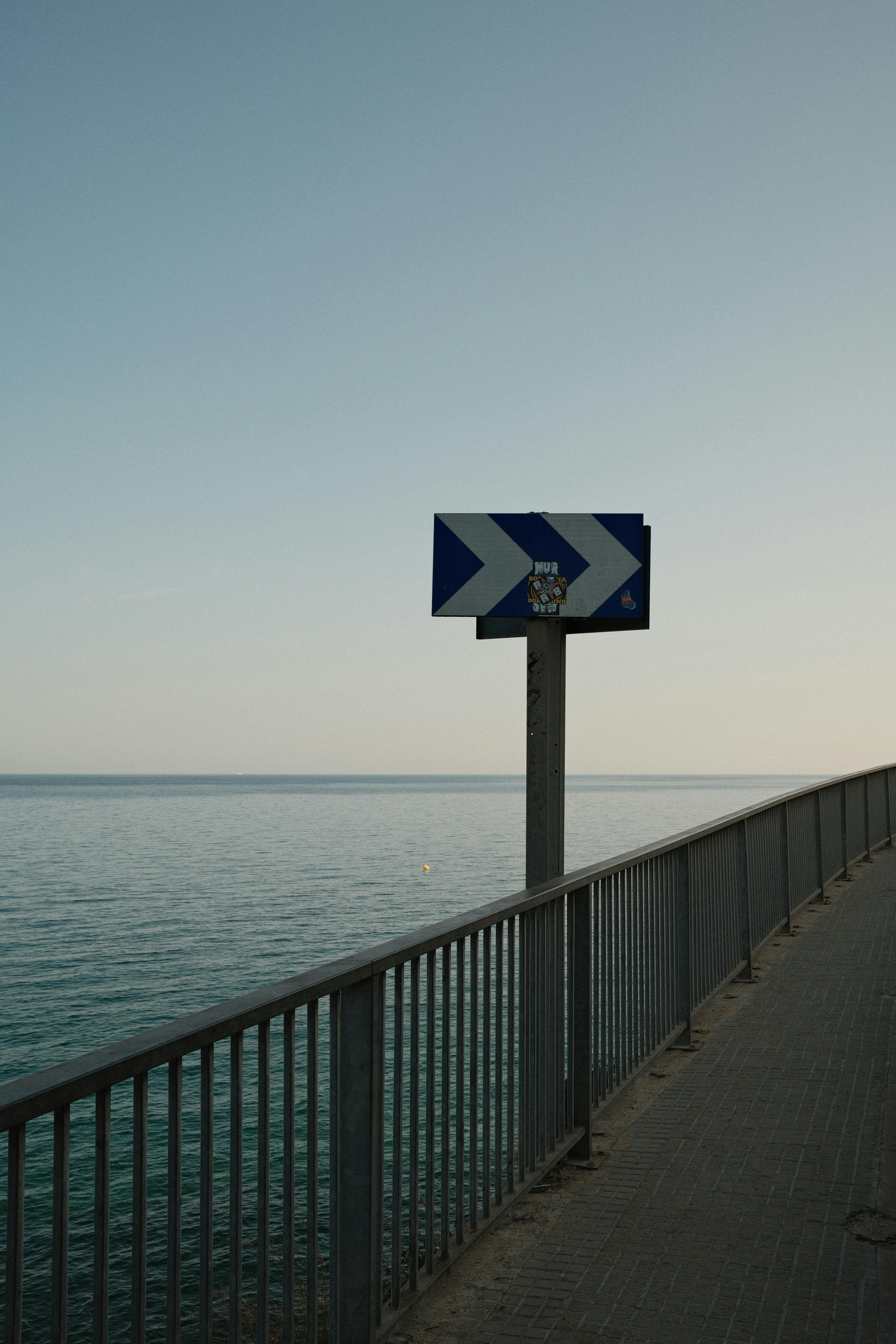 Seaside Walkway with Directional Sign and Ocean View · Free Stock Photo