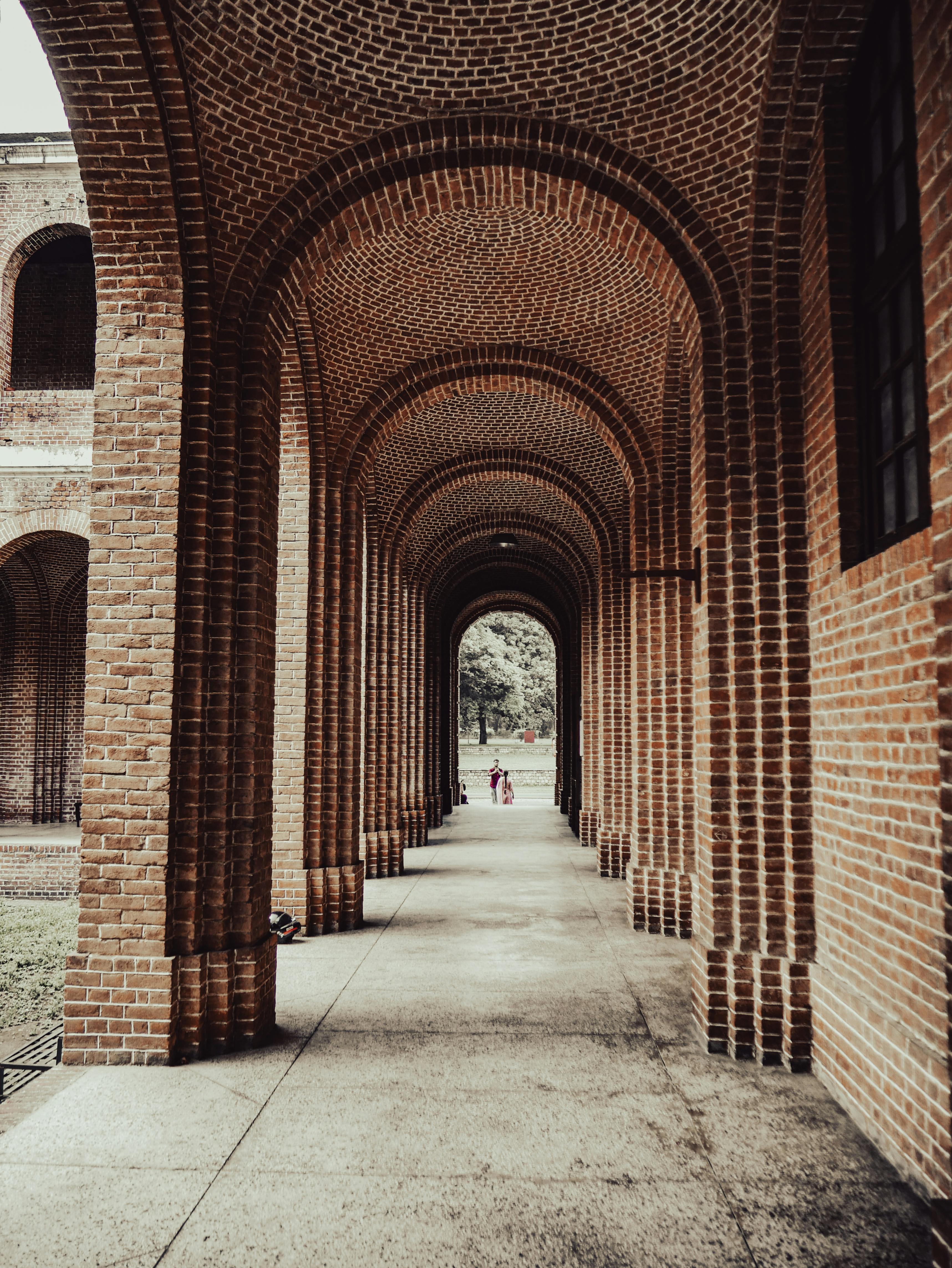 Elegant Red Brick Archway Corridor Perspective · Free Stock Photo