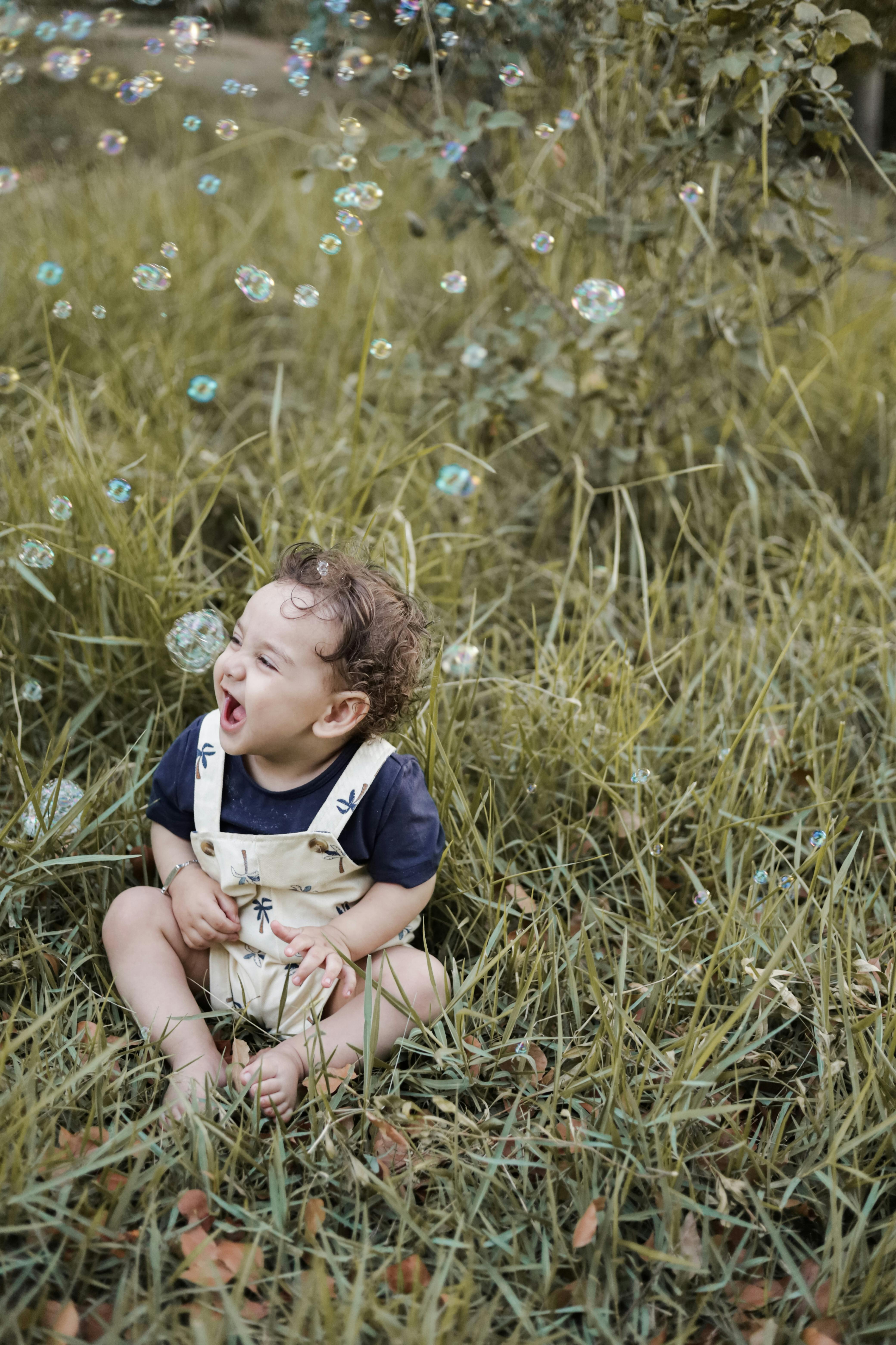 Joyful Baby Playing with Bubbles in Grass · Free Stock Photo