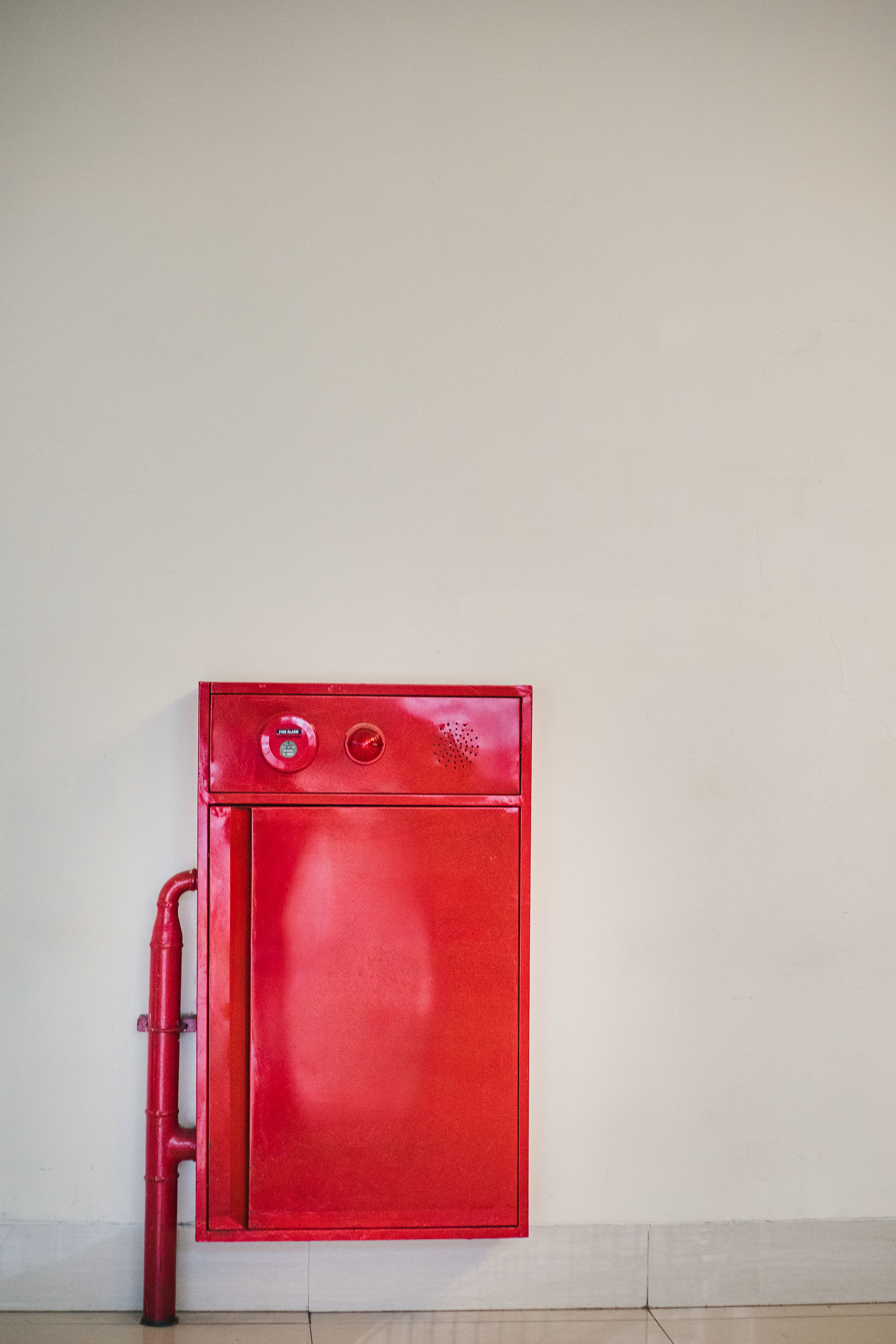 Minimalist Red Fire Safety Box Against White Wall · Free Stock Photo