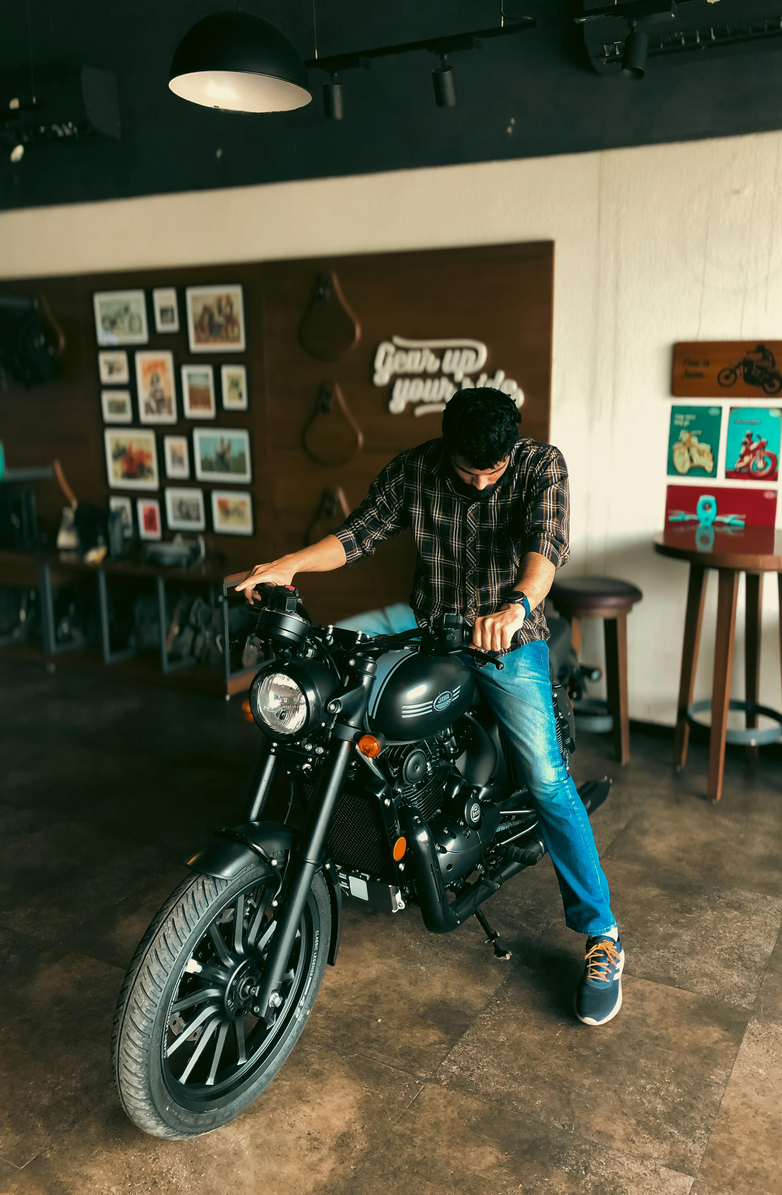 Young man posing with a classic motorcycle indoors · Free Stock Photo