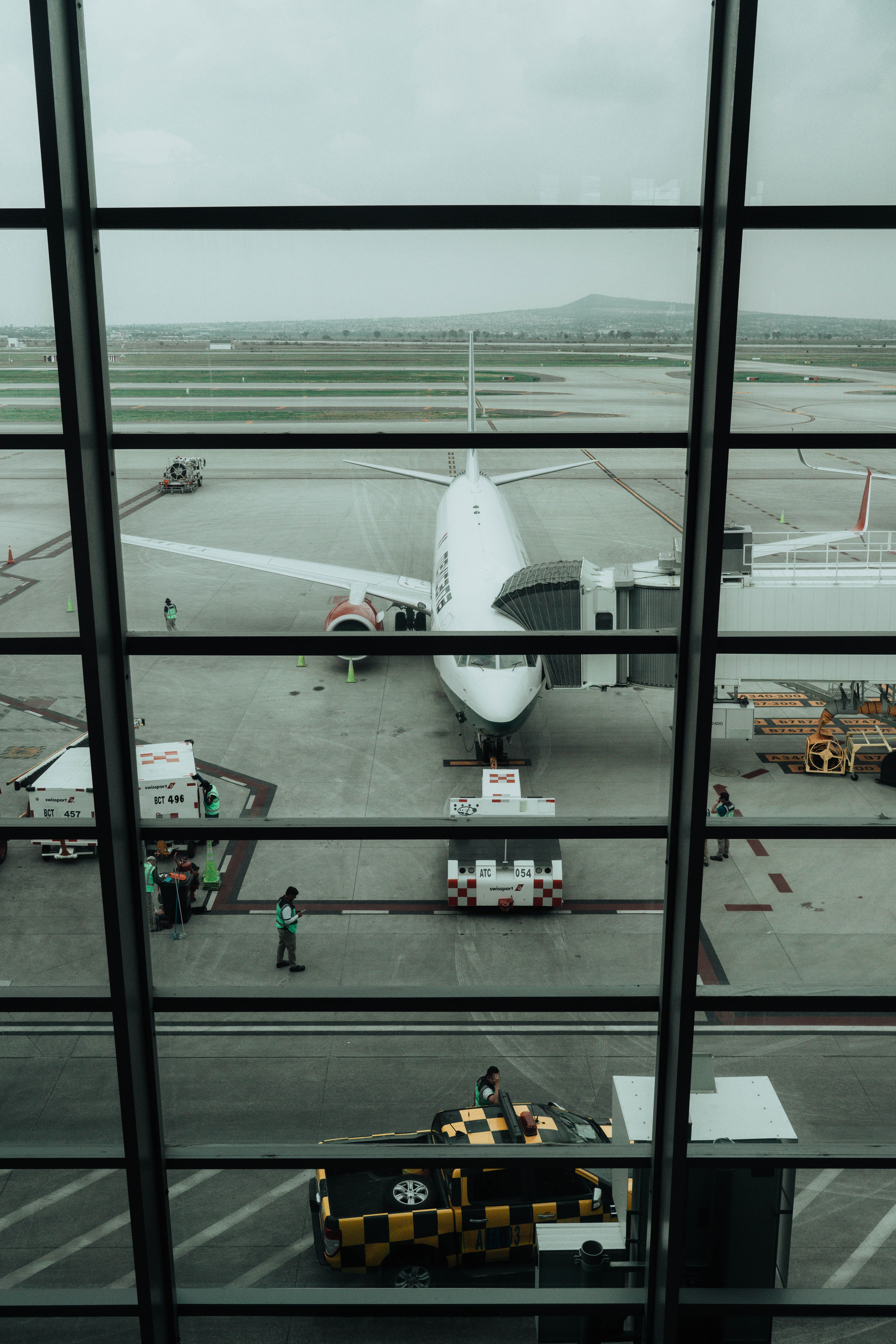 Airplane at Airport Terminal through Glass · Free Stock Photo