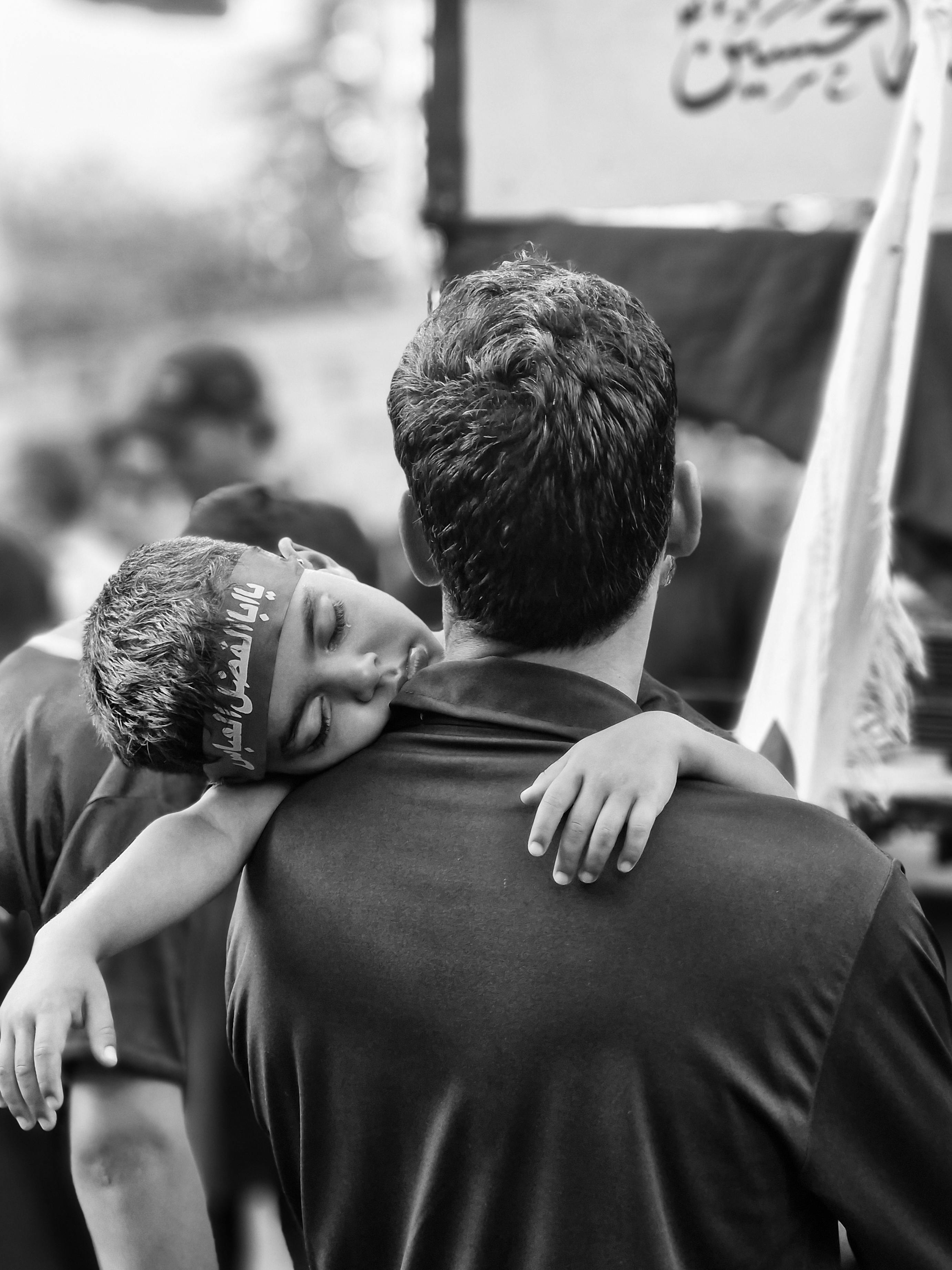 Padre Cargando A Su Hijo Dormido En Un Evento Cultural · Foto de stock gratuita