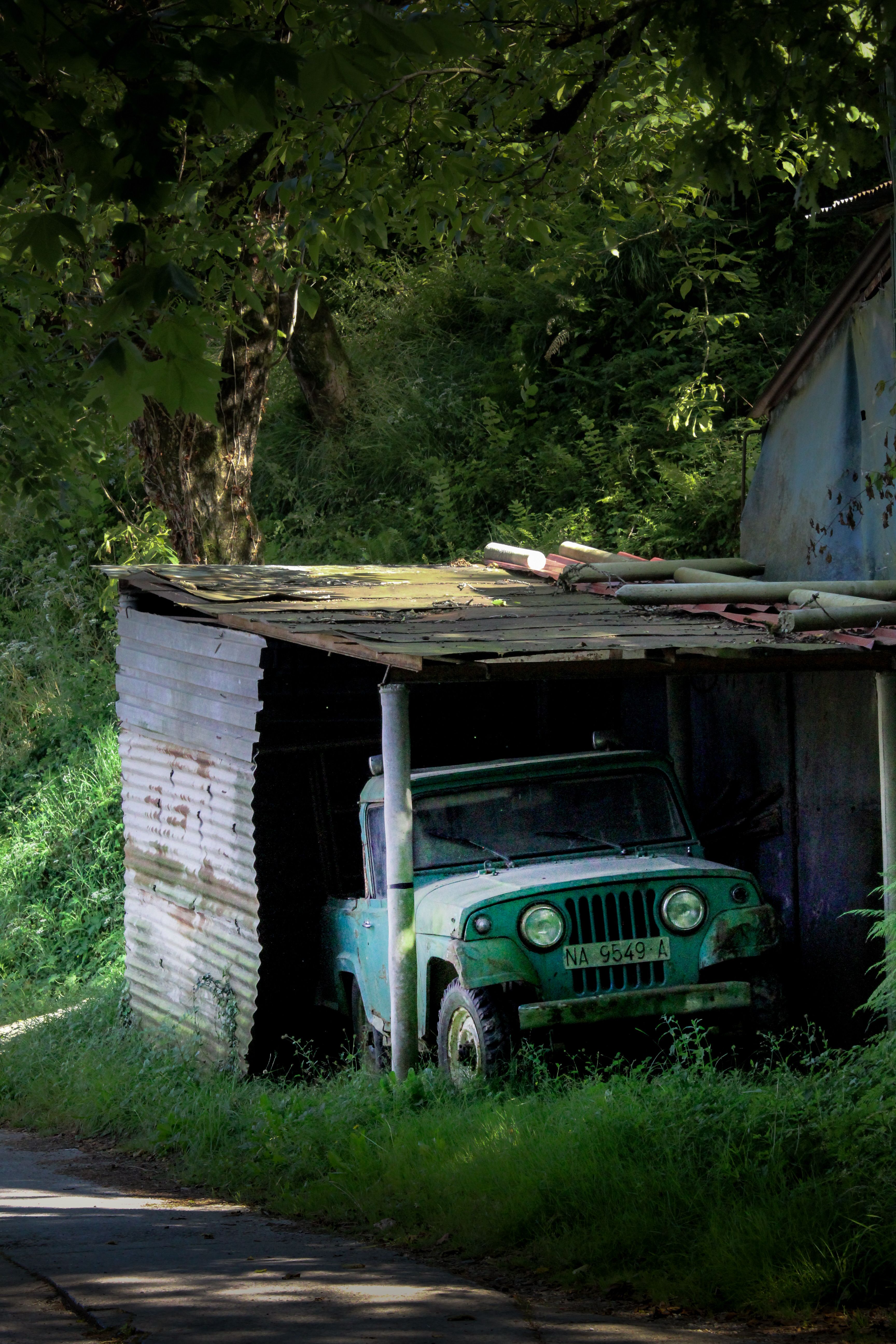 Vintage Green Jeep in Rustic Outdoor Garage · Free Stock Photo