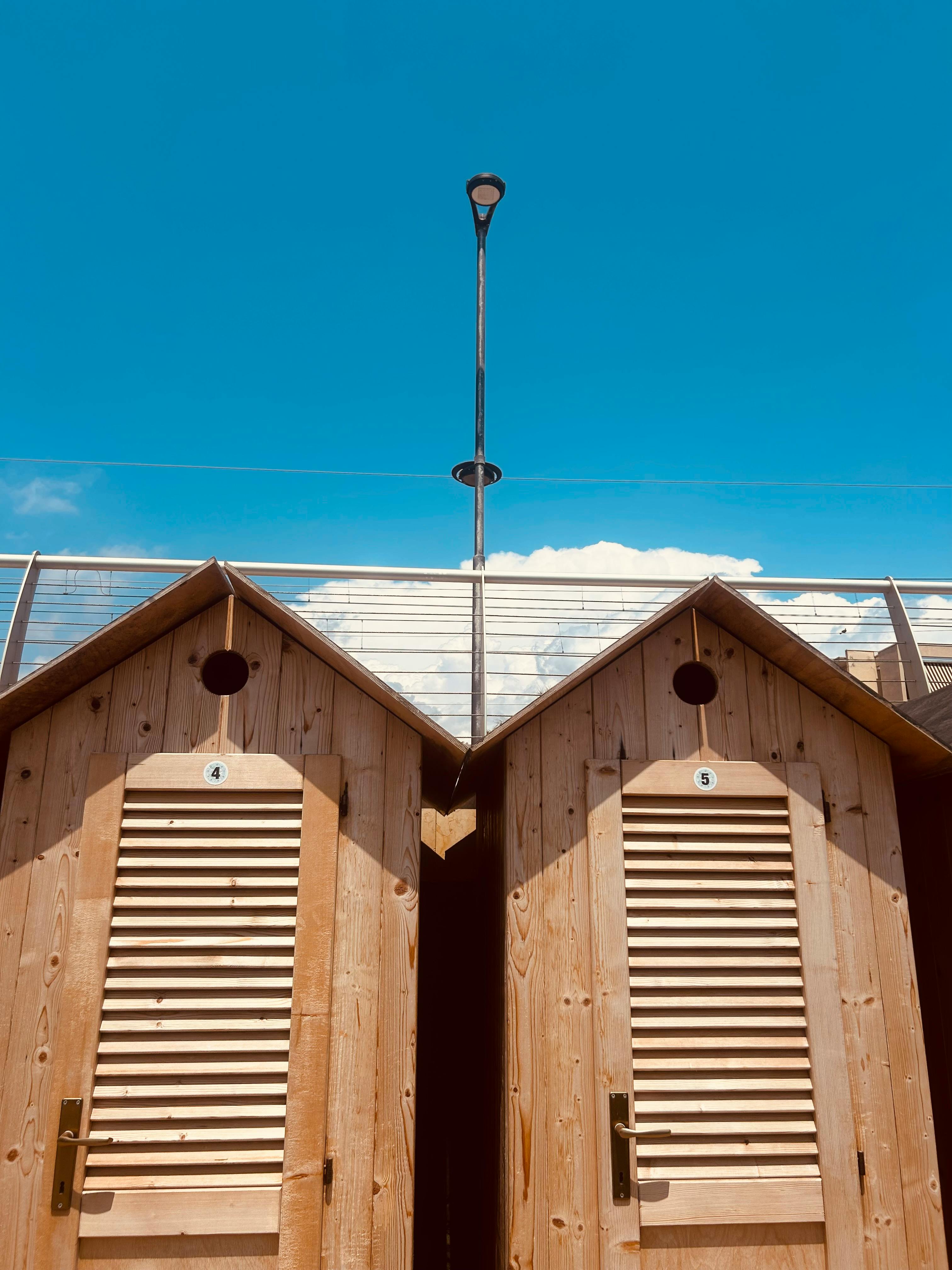 Rustic Wooden Beach Huts Under Clear Blue Sky · Free Stock Photo