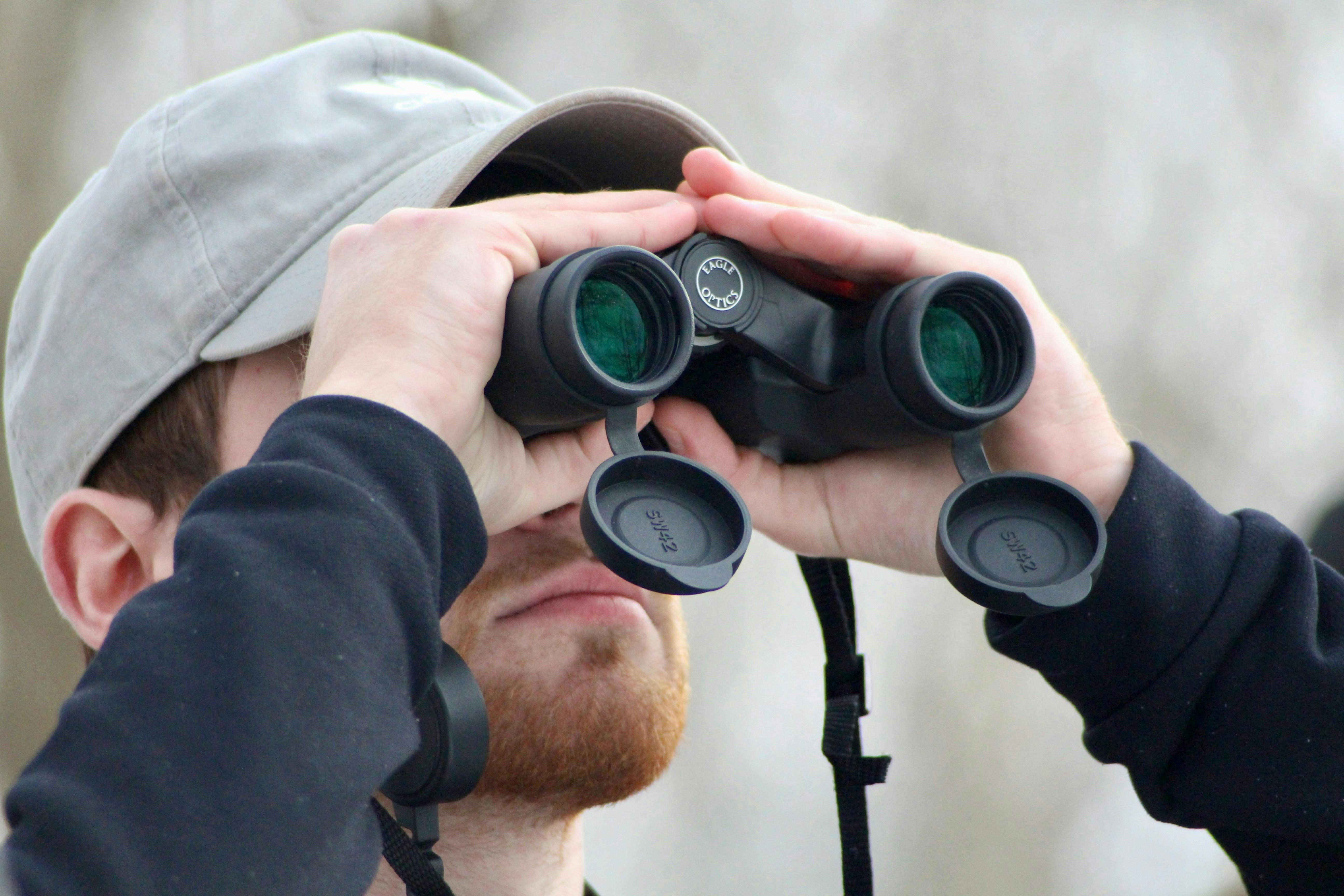 Young Man Birdwatching with Binoculars Outdoors · Free Stock Photo