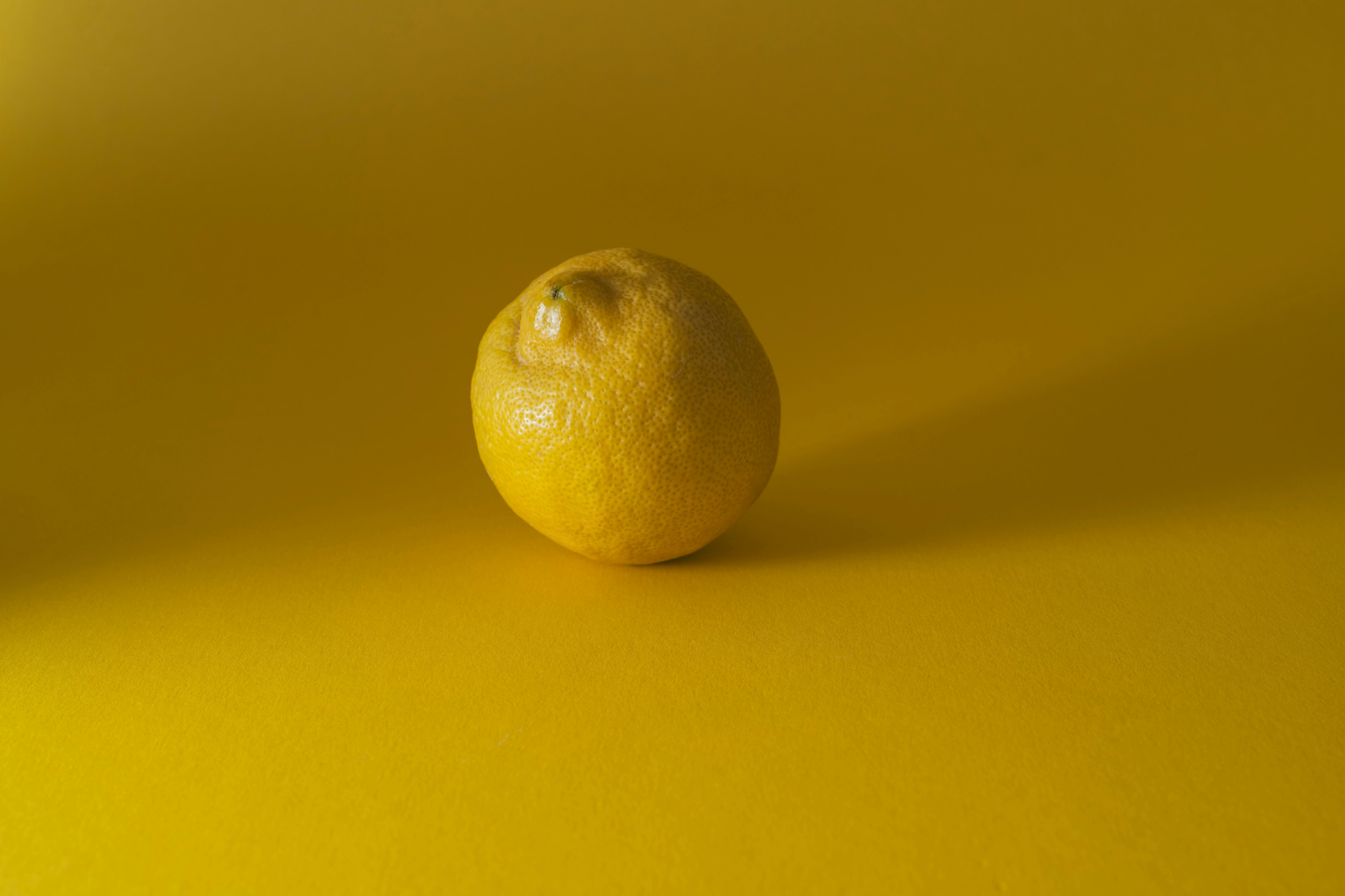 Vibrant Lemon on Yellow Minimalist Background · Free Stock Photo
