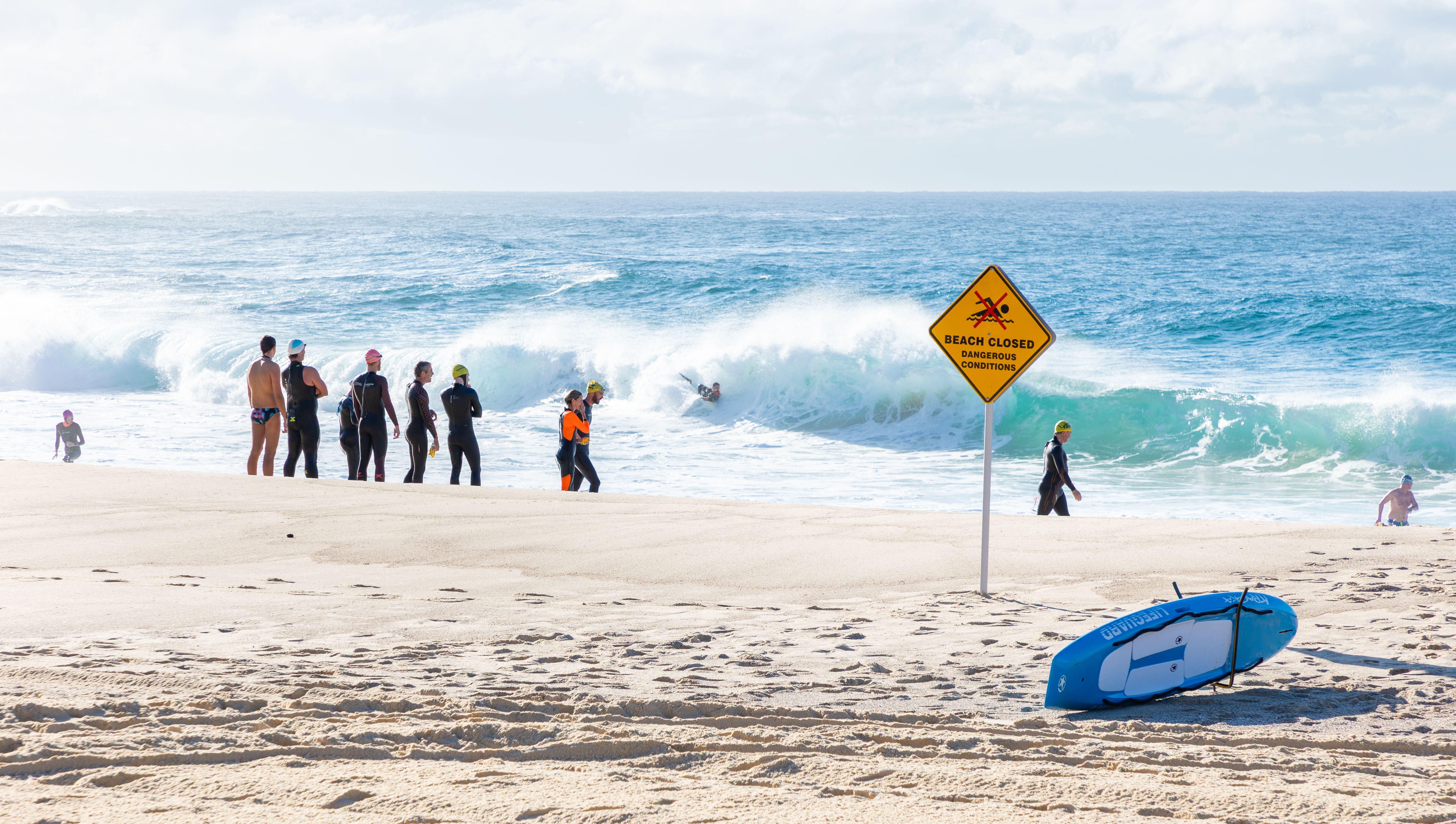 Blue Surfboard at Shoreline Near Signage · Free Stock Photo