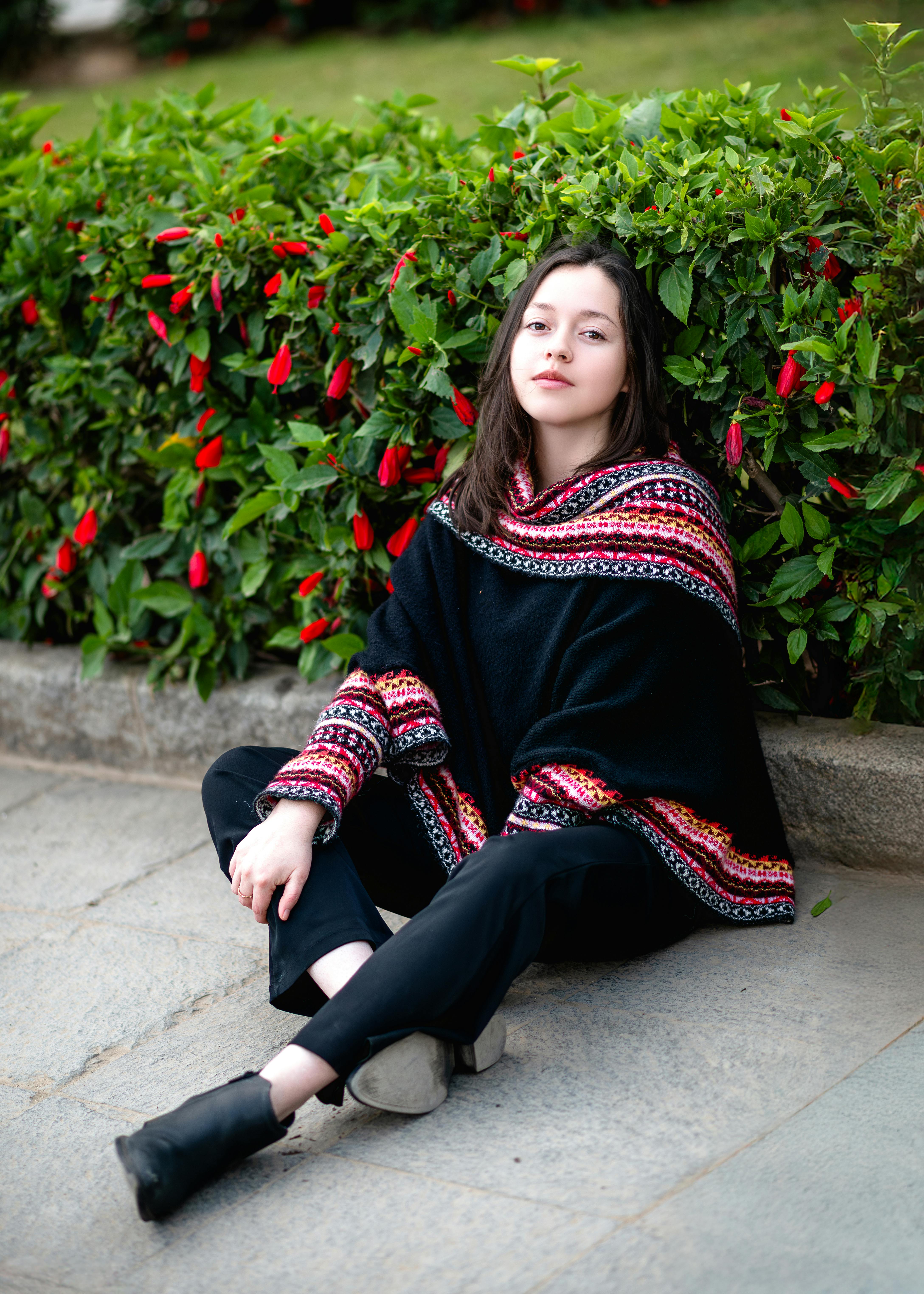 Mujer Joven Con Poncho Tradicional Sentada Al Aire Libre · Foto de stock gratuita