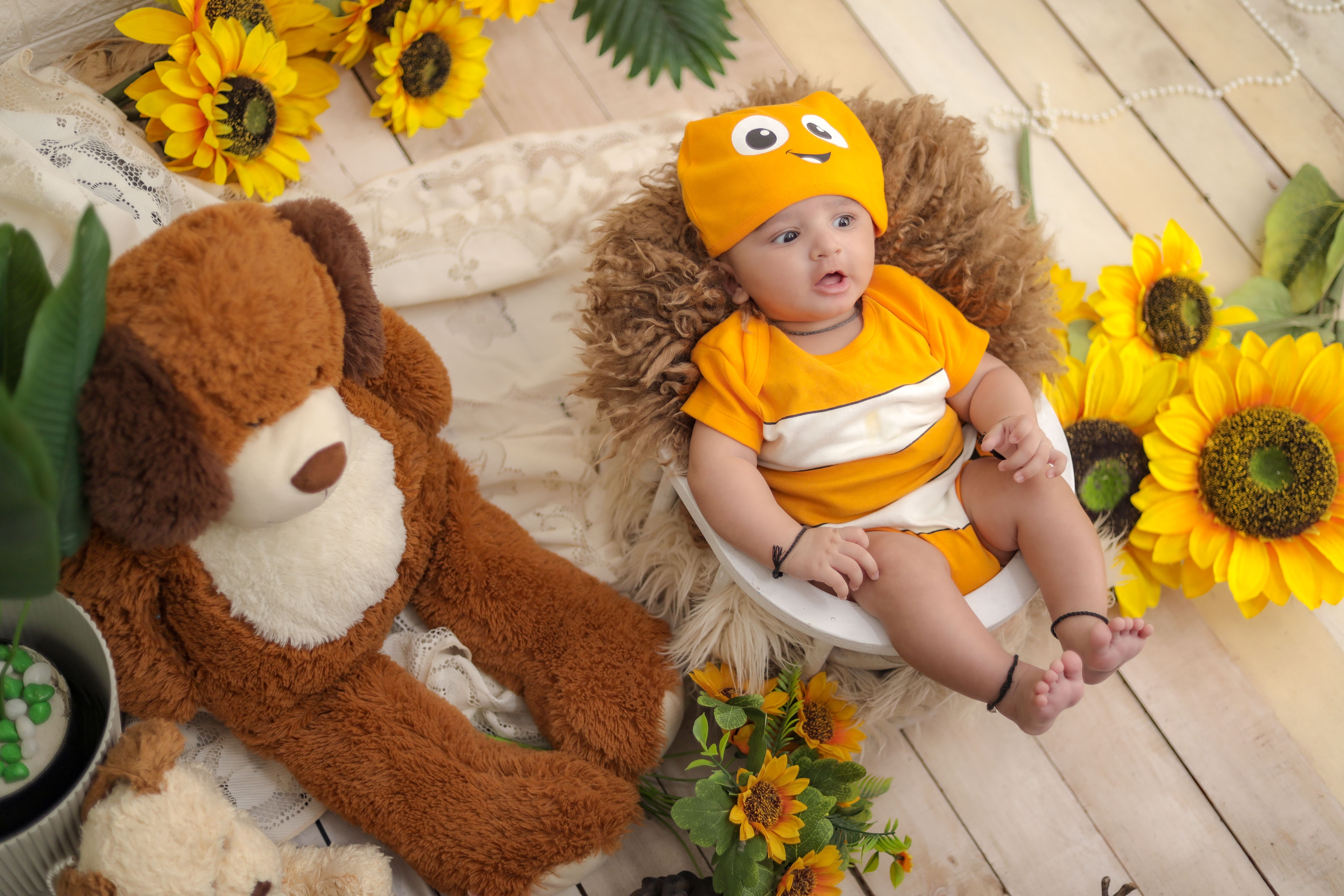 Adorable Baby in Orange Outfit with Stuffed Toy · Free Stock Photo