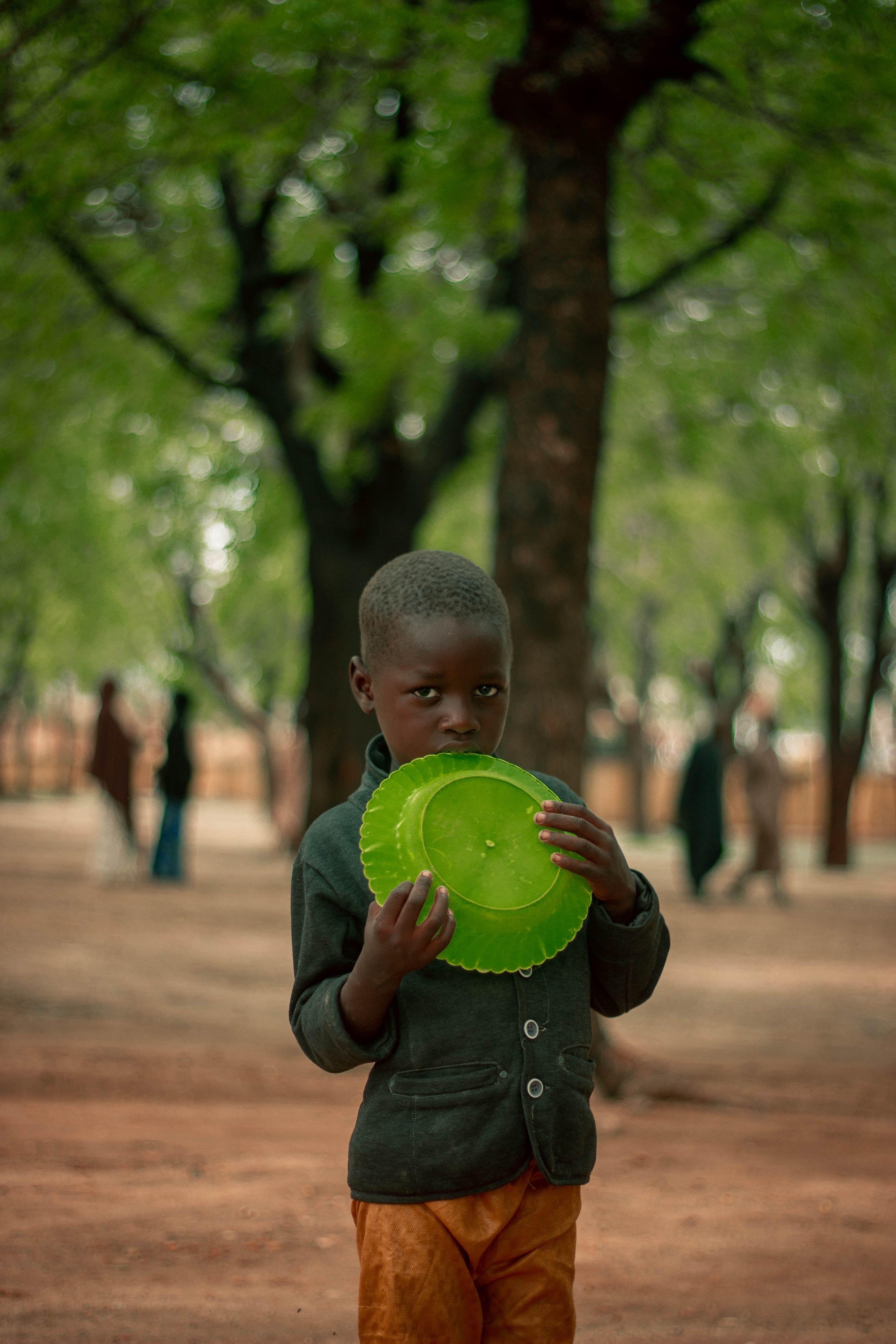 Child Holding Green Plate in Forested Area · Free Stock Photo