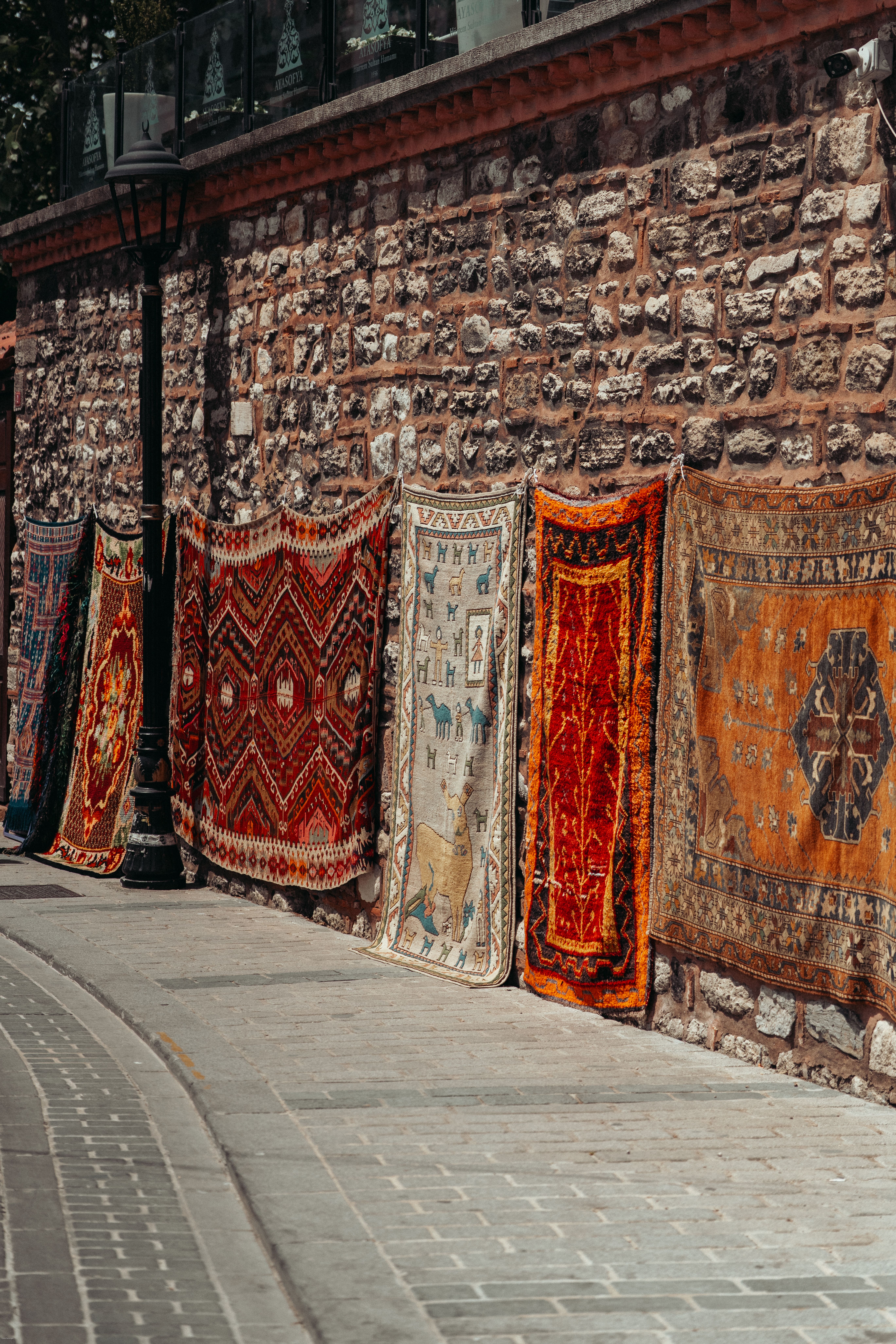 Colorful Traditional Rugs Displayed on Stone Wall Outdoors · Free Stock ...