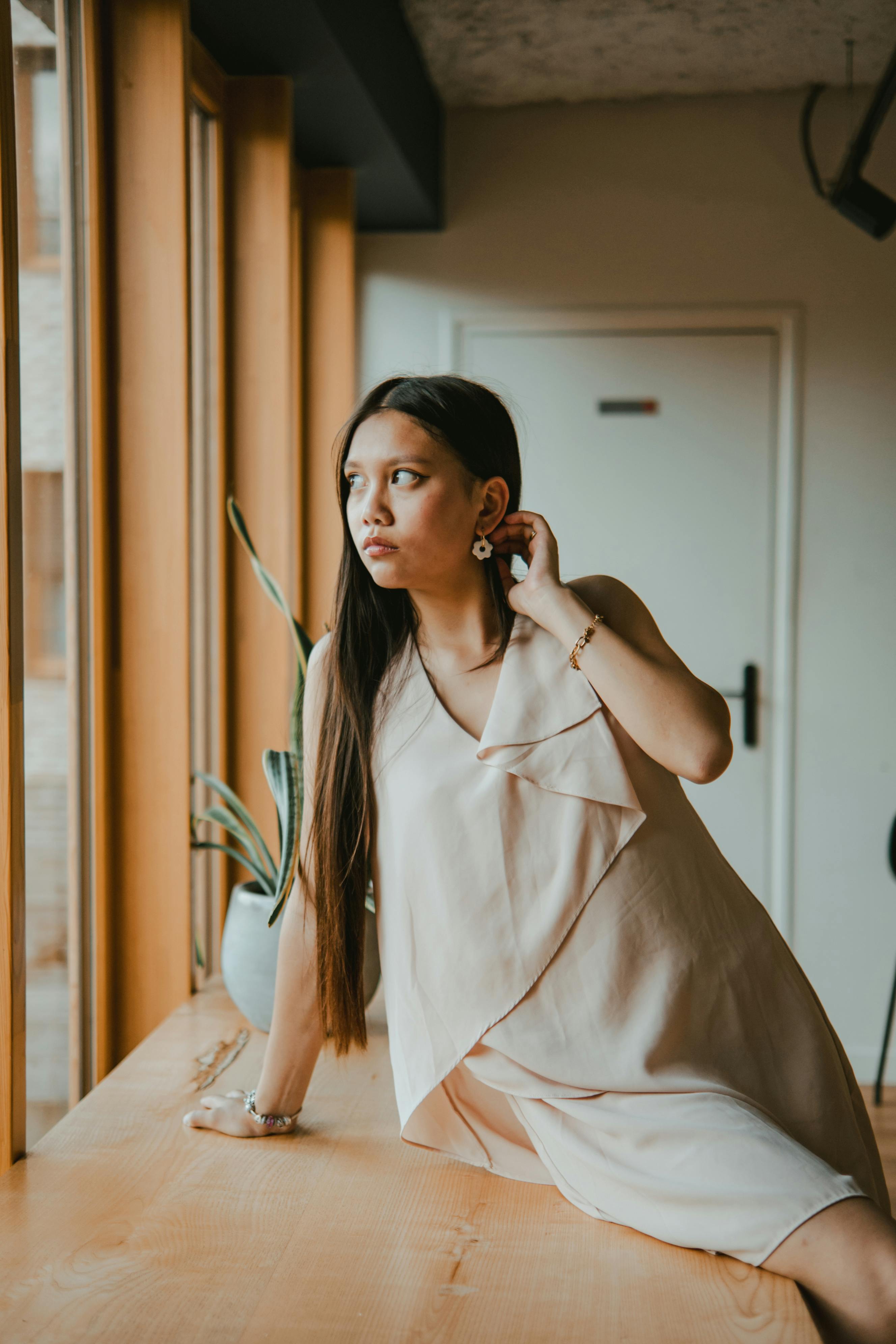 Mujer Elegante Posando Junto A Una Ventana Interior Iluminada Por El Sol · Foto de stock gratuita