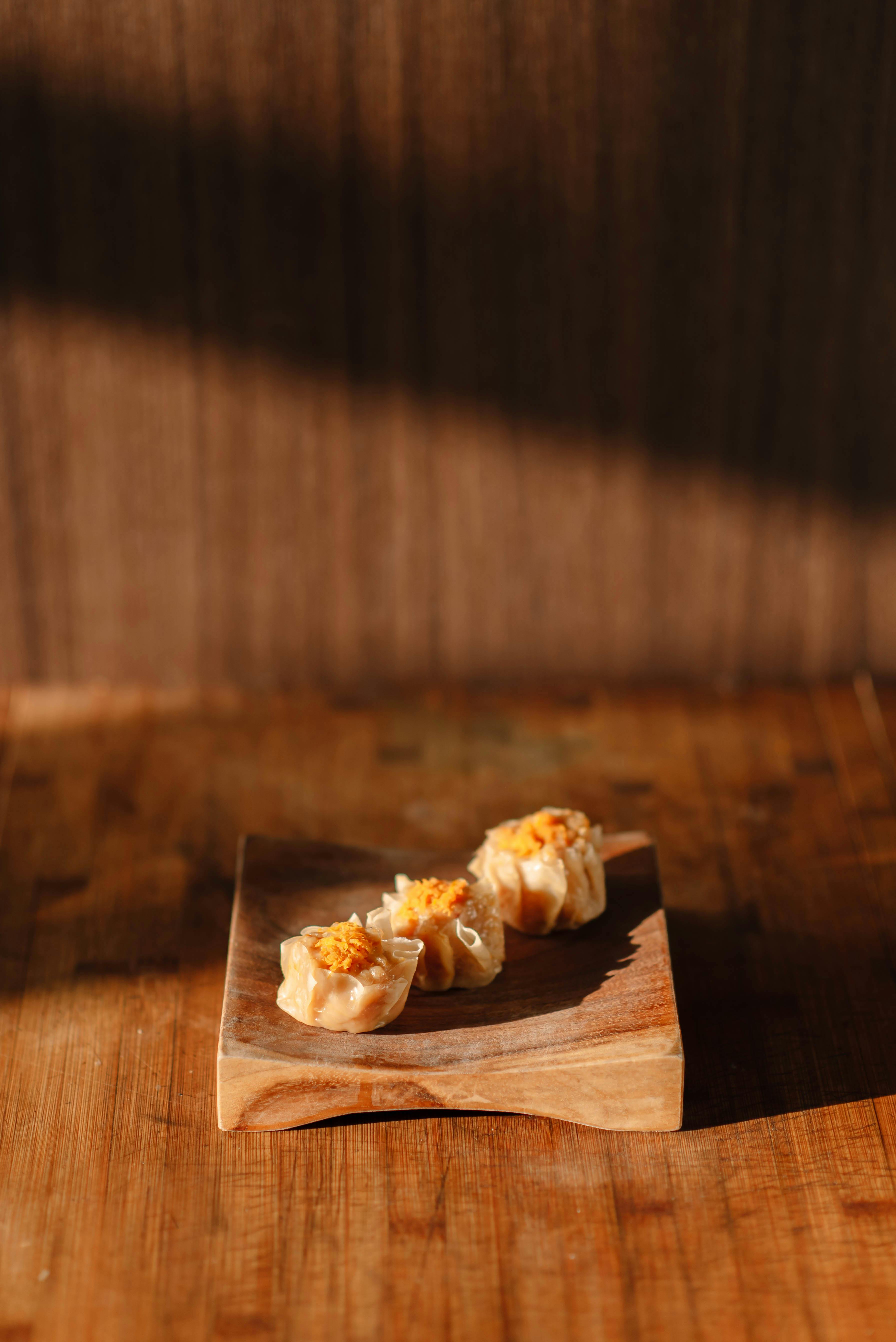 Artistic Dim Sum on Wooden Plate in Warm Lighting · Free Stock Photo