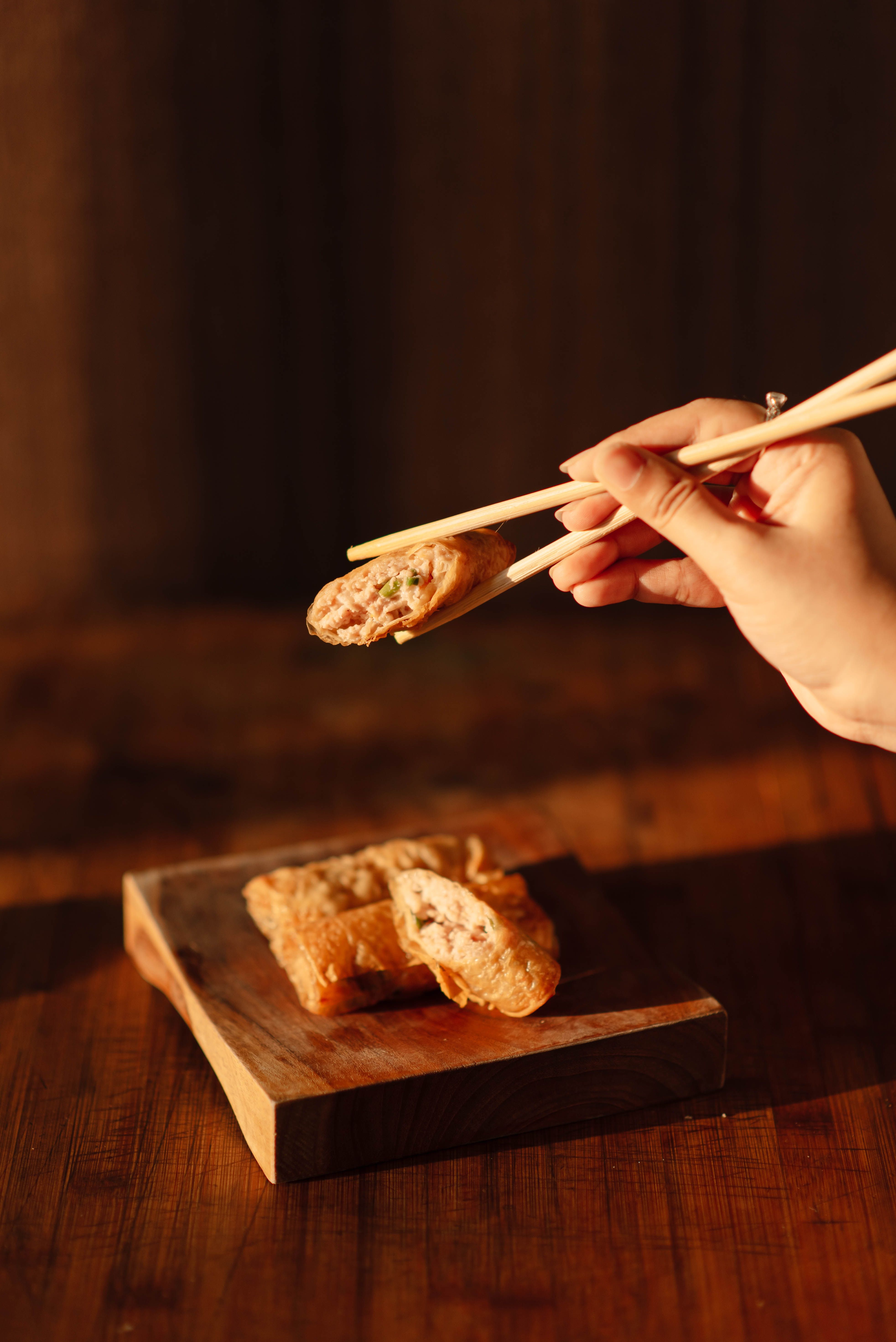 Hand Holding Tofu with Chopsticks on Wooden Board · Free Stock Photo