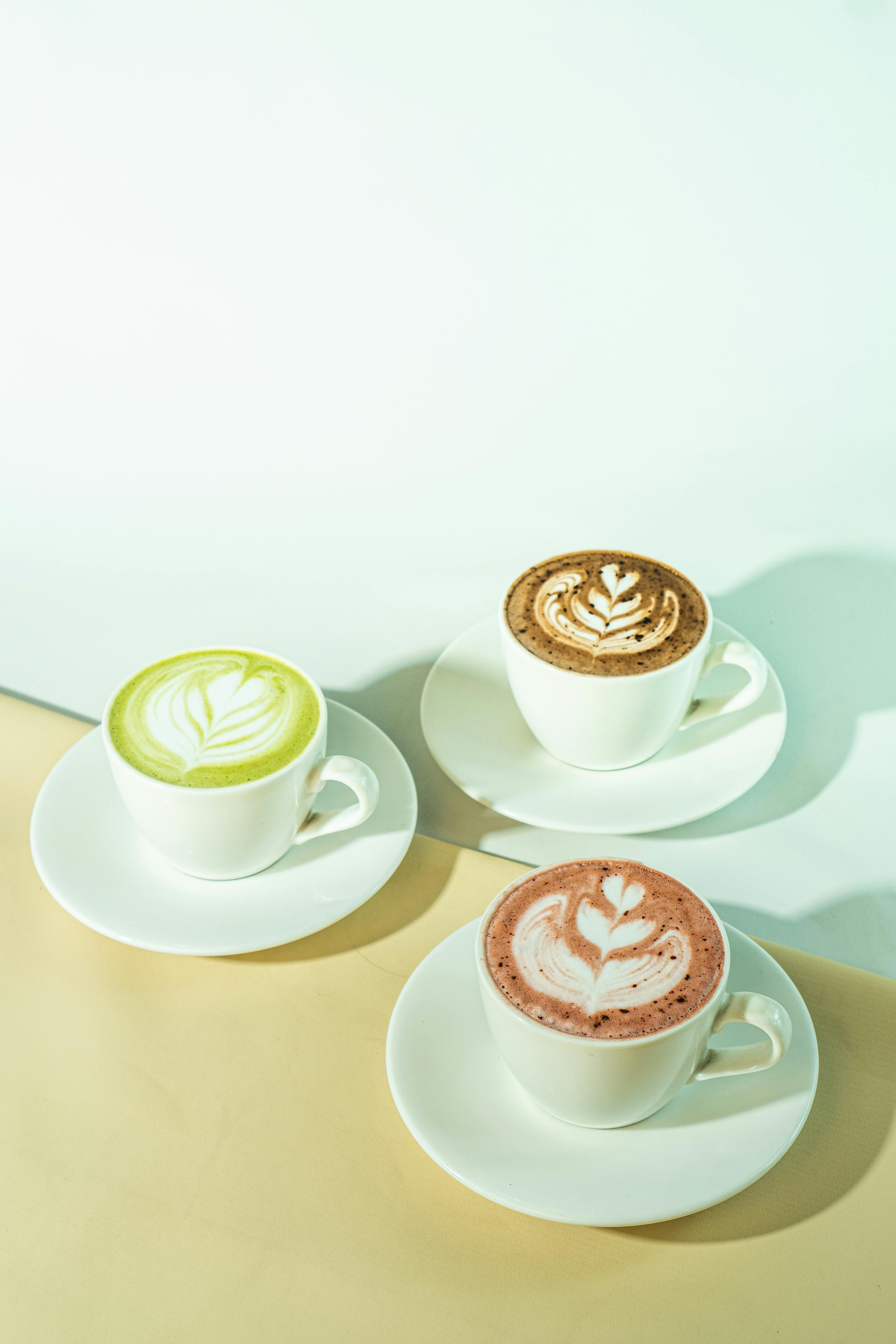 Colorful Latte Art Trio on White Table · Free Stock Photo
