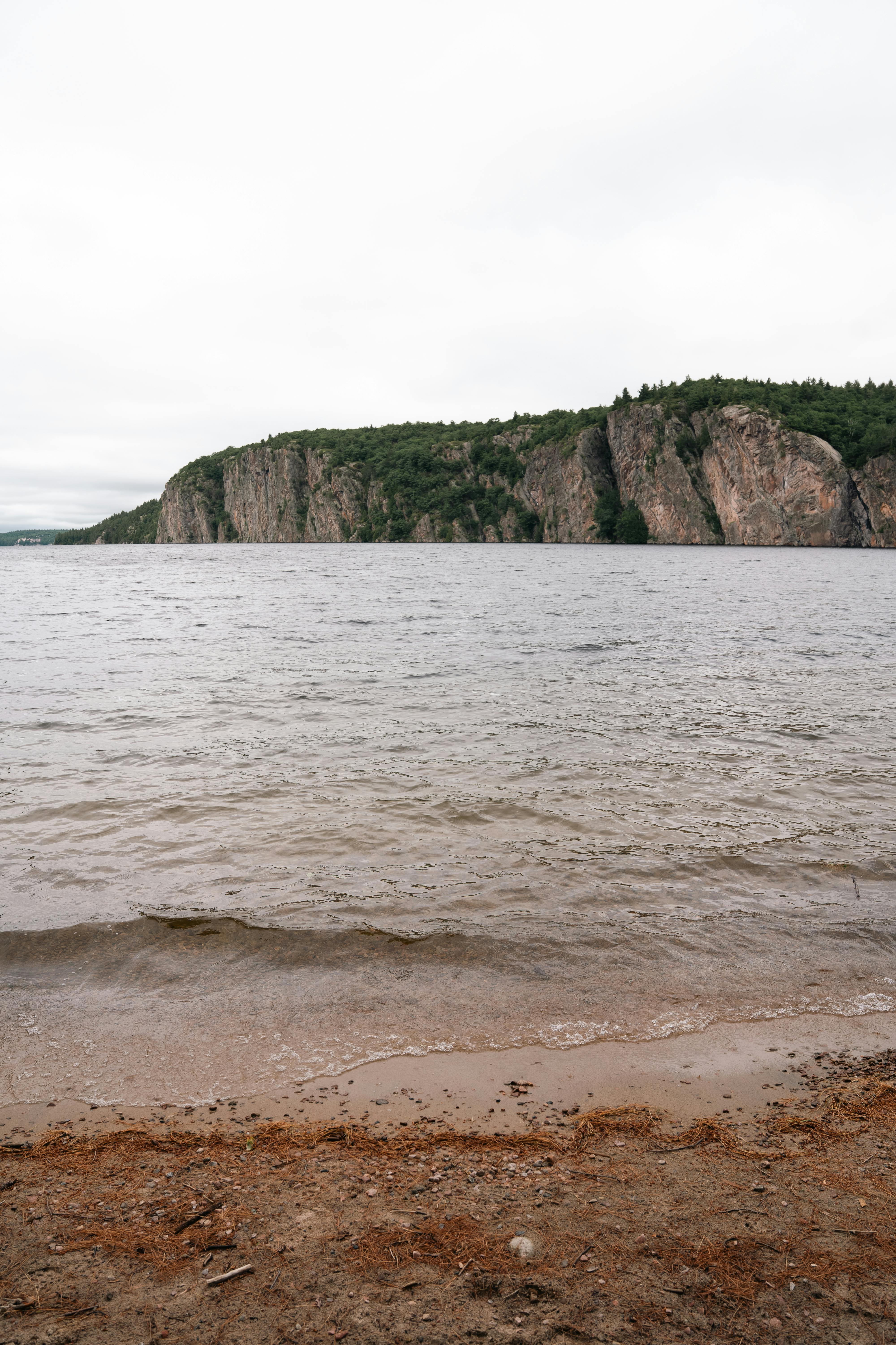 Serene Lakeside View with Rocky Cliff in Summer · Free Stock Photo