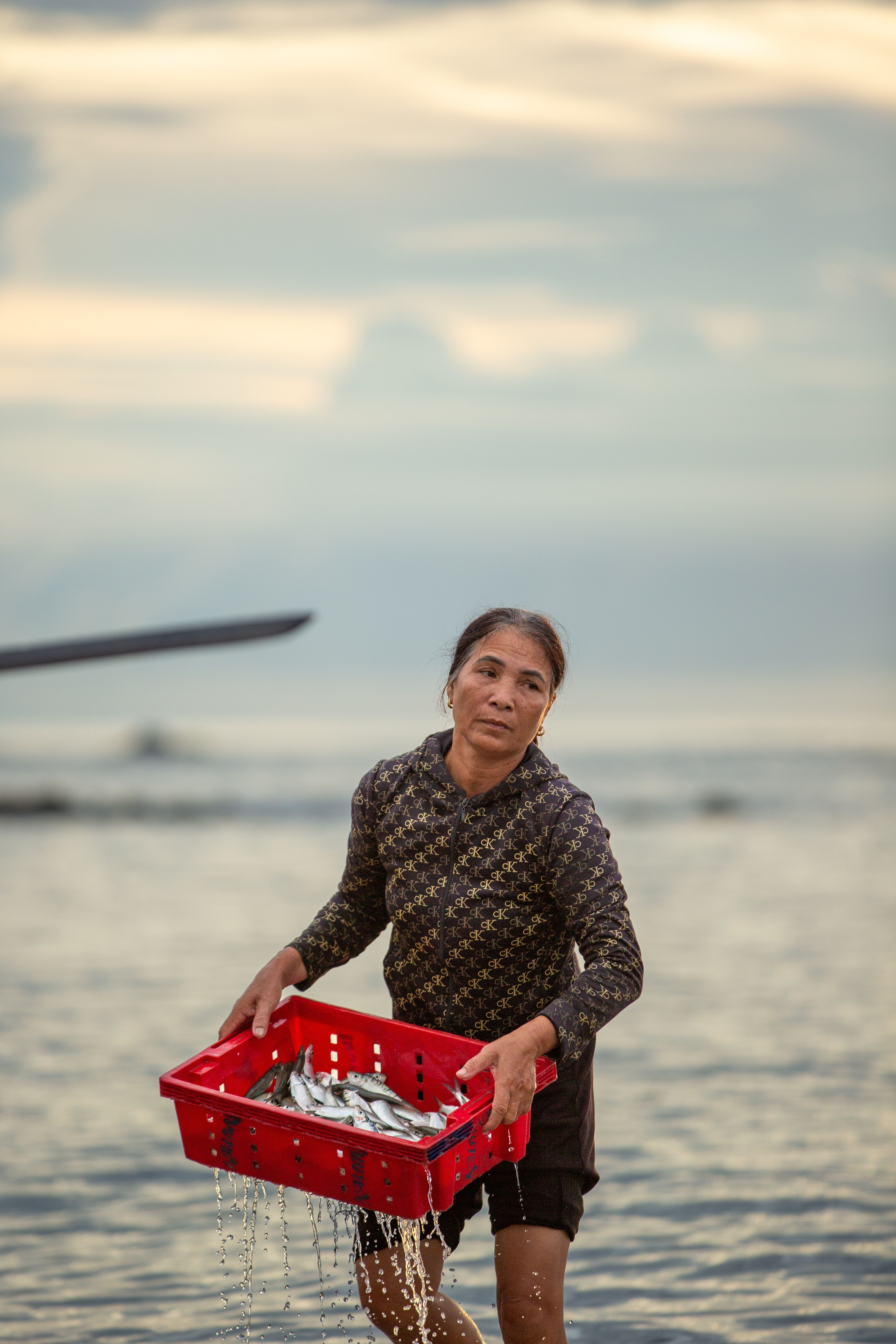 Pescadora Sosteniendo Una Caja Roja De Pescado Fresco En El Mar · Foto ...
