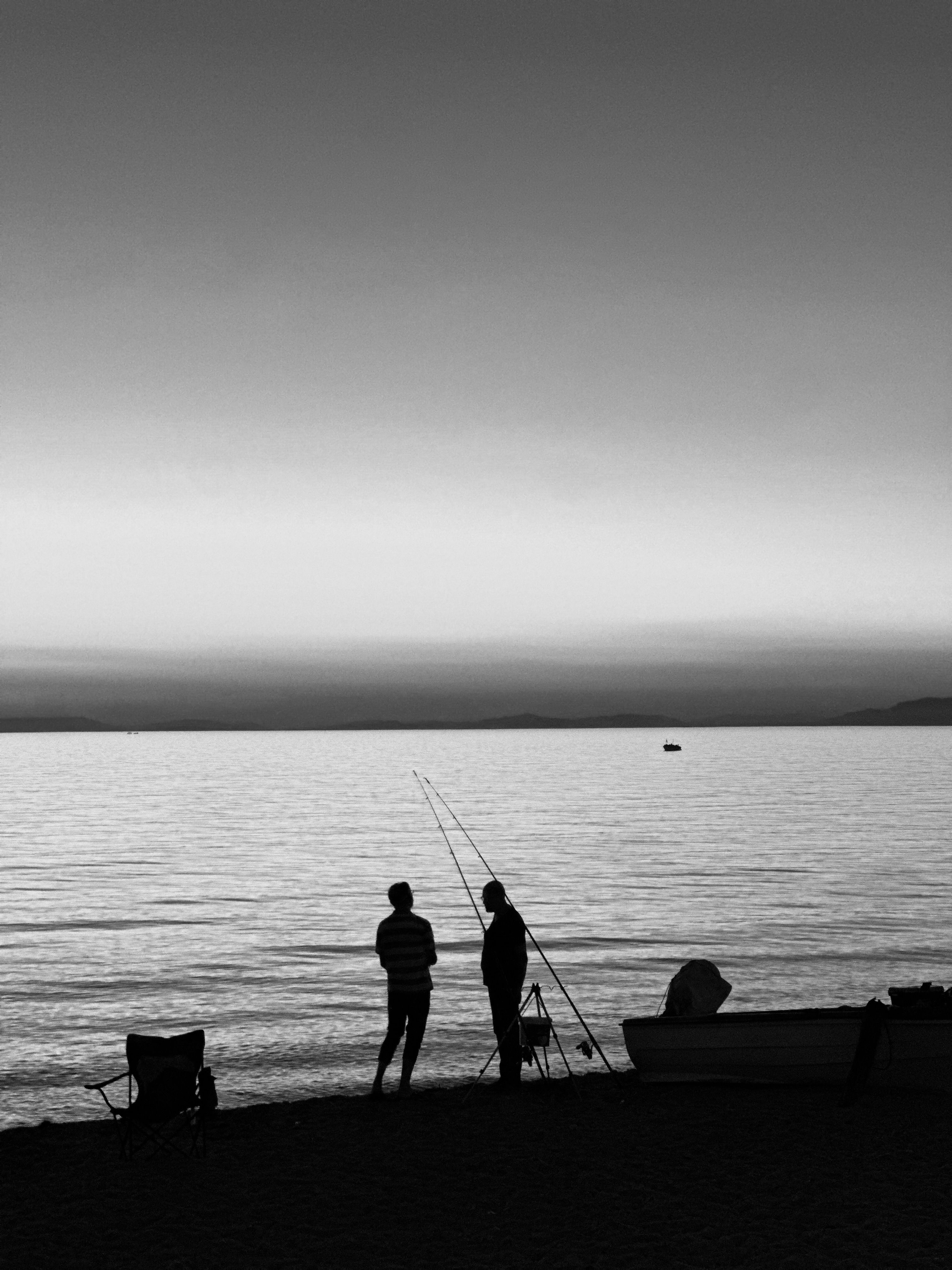 Silhouetted Figures Fishing at Sunset by the Sea · Free Stock Photo