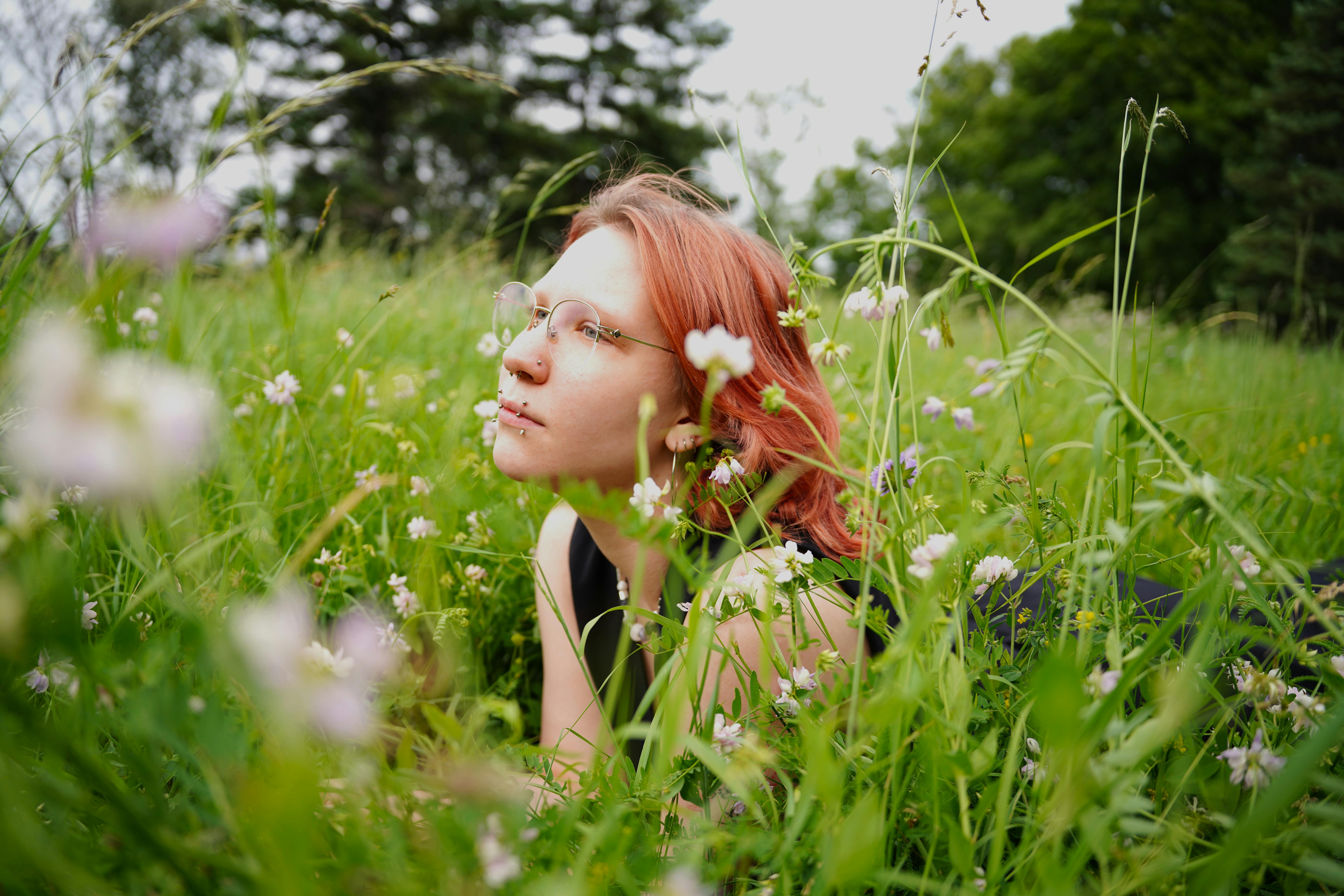 Young Woman in a Lush Green Meadow with Wildflowers · Free Stock Photo