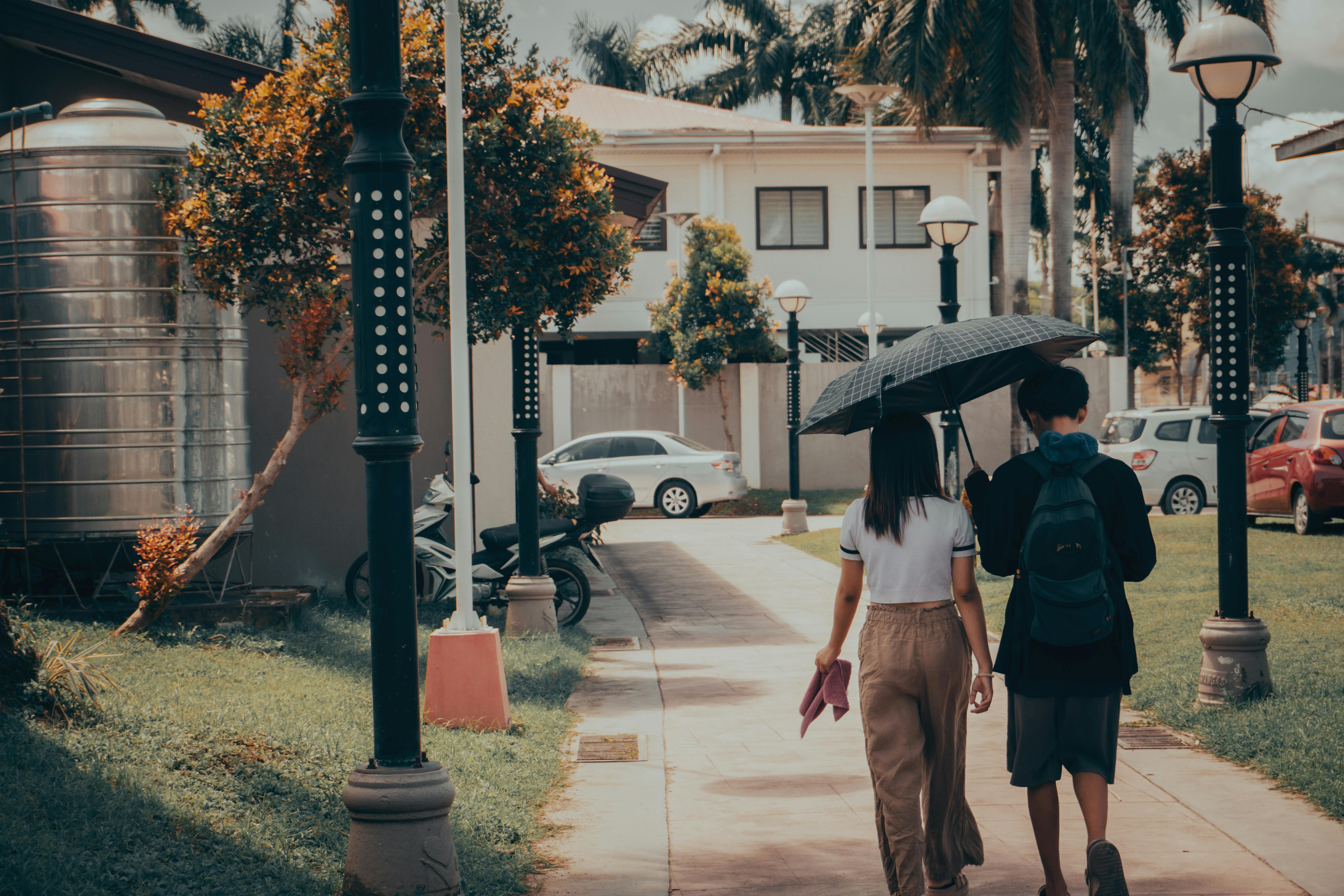 Young Couple Walking with Umbrella in Park · Free Stock Photo