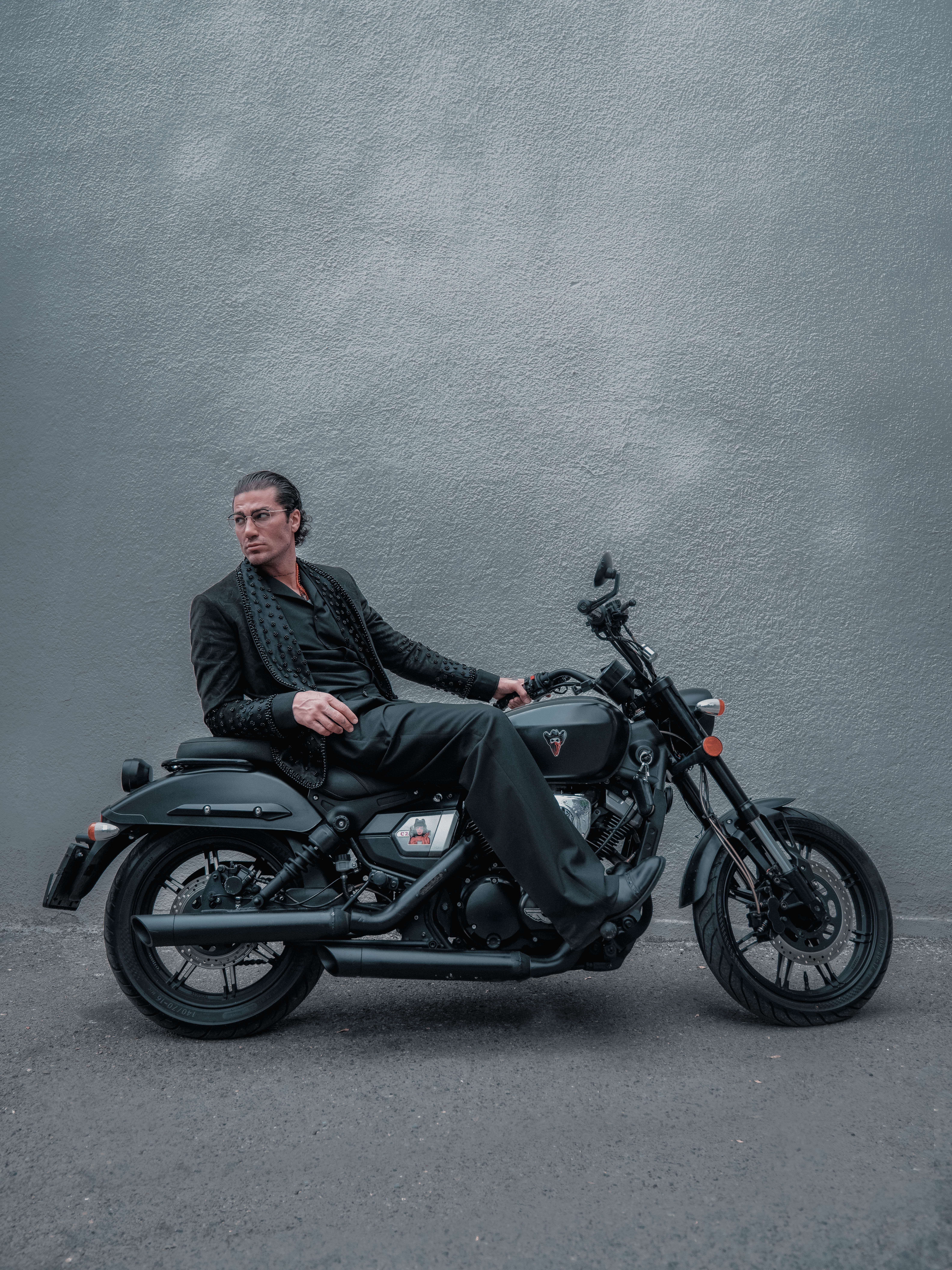 Stylish Man Posing on Motorcycle Against Grey Wall · Free Stock Photo