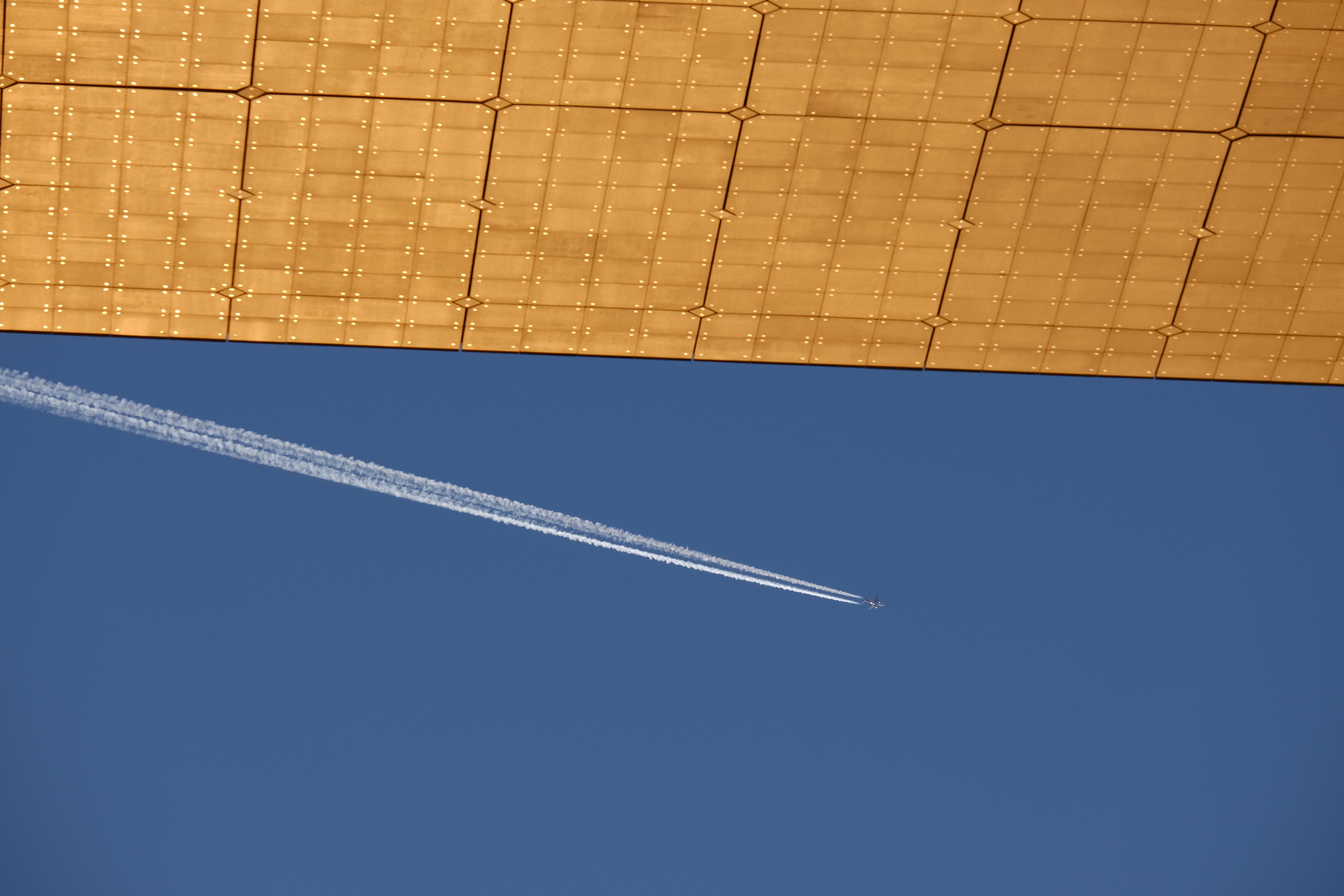 Jet Contrail Under Solar Panel in Clear Blue Sky · Free Stock Photo