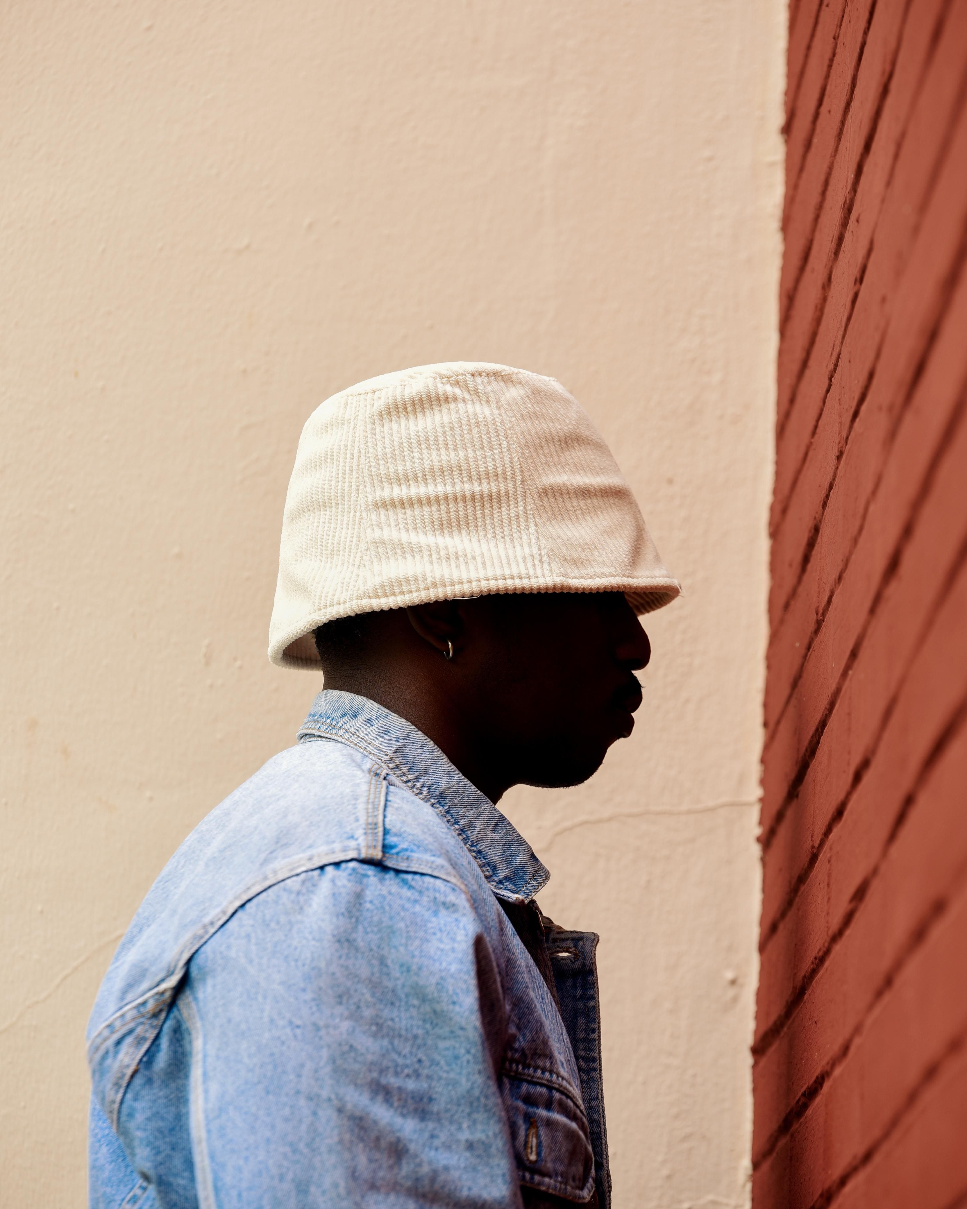 Man in Denim Jacket with Bucket Hat Facing Brick Wall · Free Stock Photo