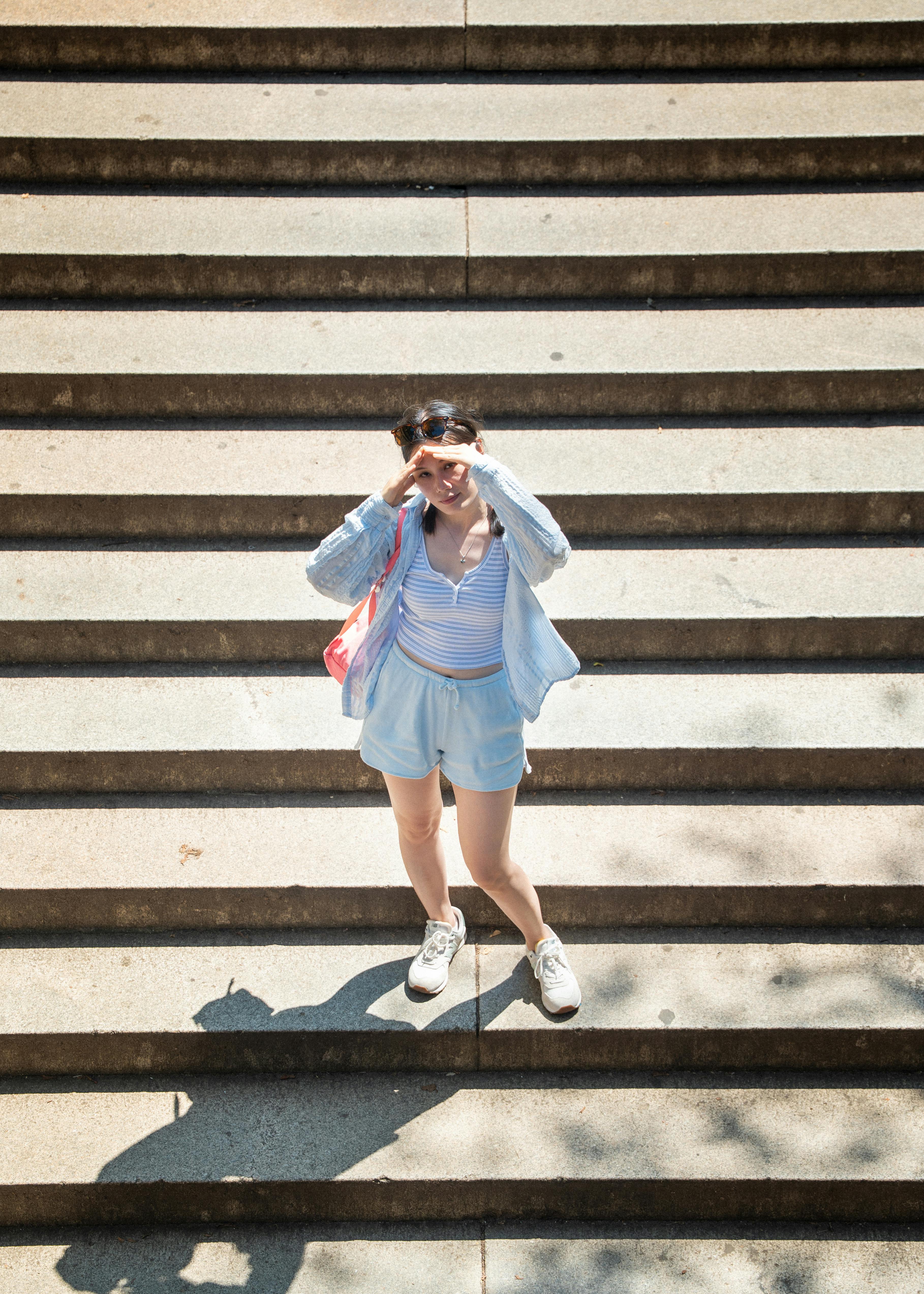 Young Woman Standing on Sunlit Steps in NYC · Free Stock Photo
