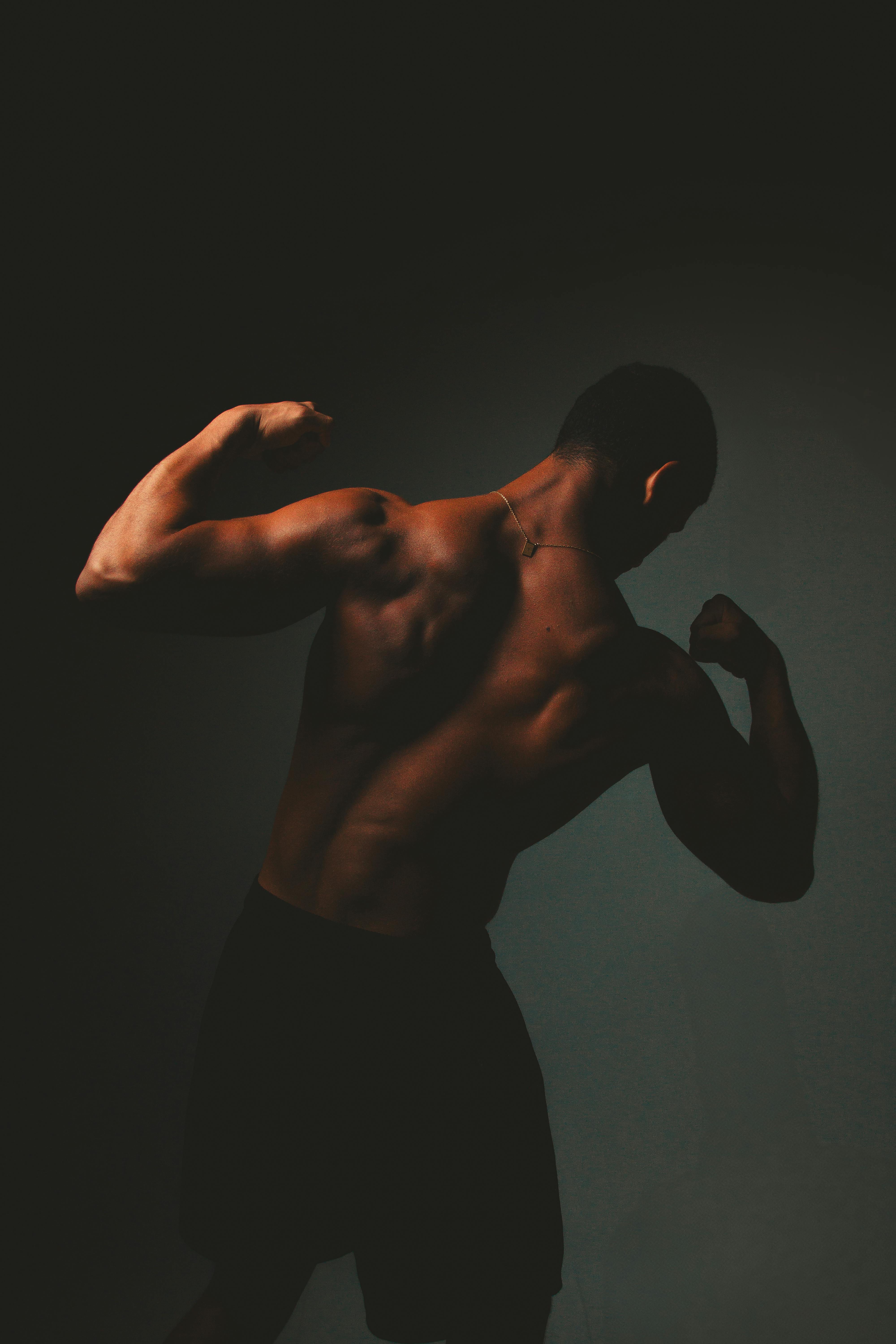 Silhouette of a Muscular Man Flexing in Low Light · Free Stock Photo