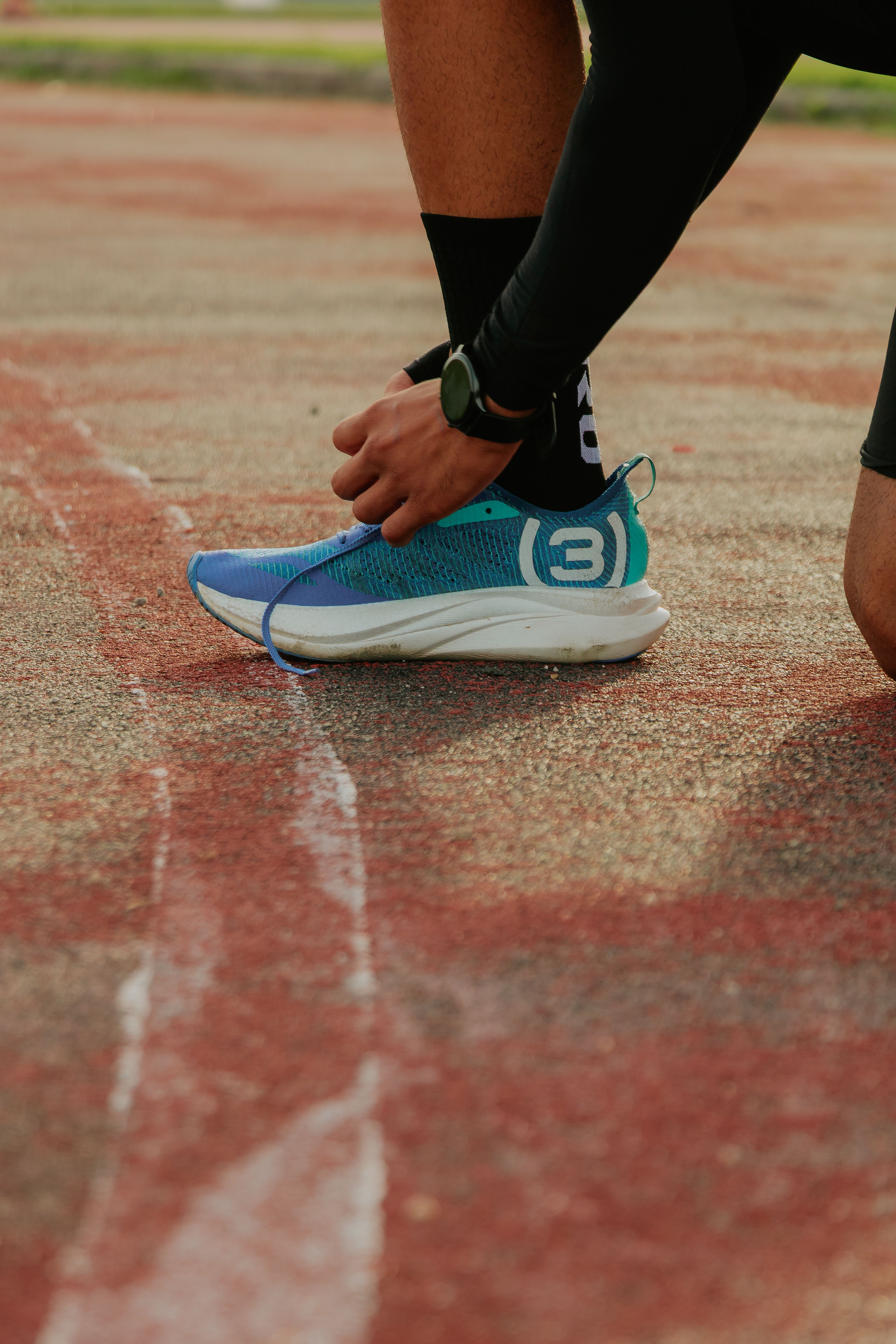 Runner Tying Shoe on Outdoor Track in Rio · Free Stock Photo