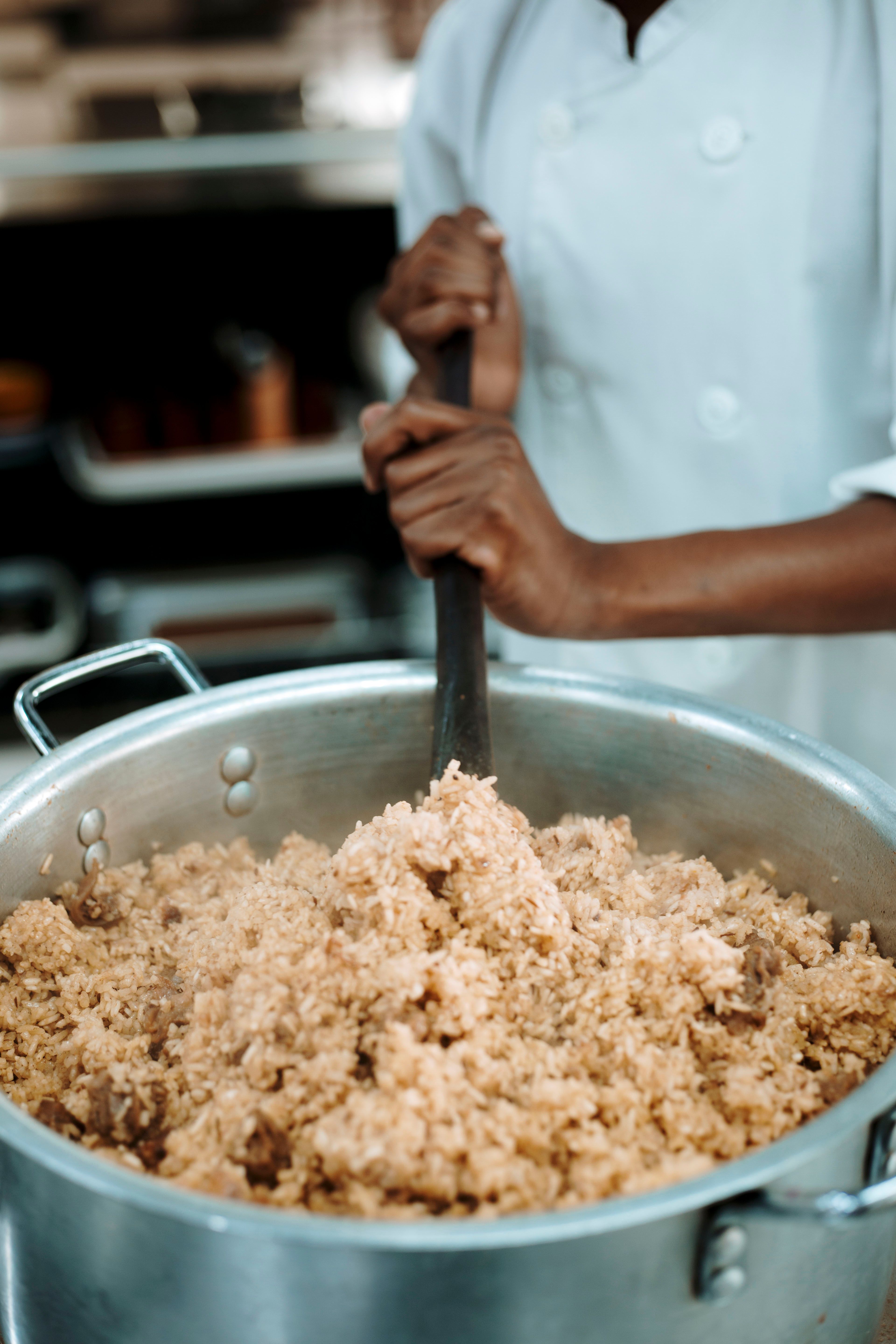 Chef Stirring Large Pot of Steaming Rice Dish · Free Stock Photo