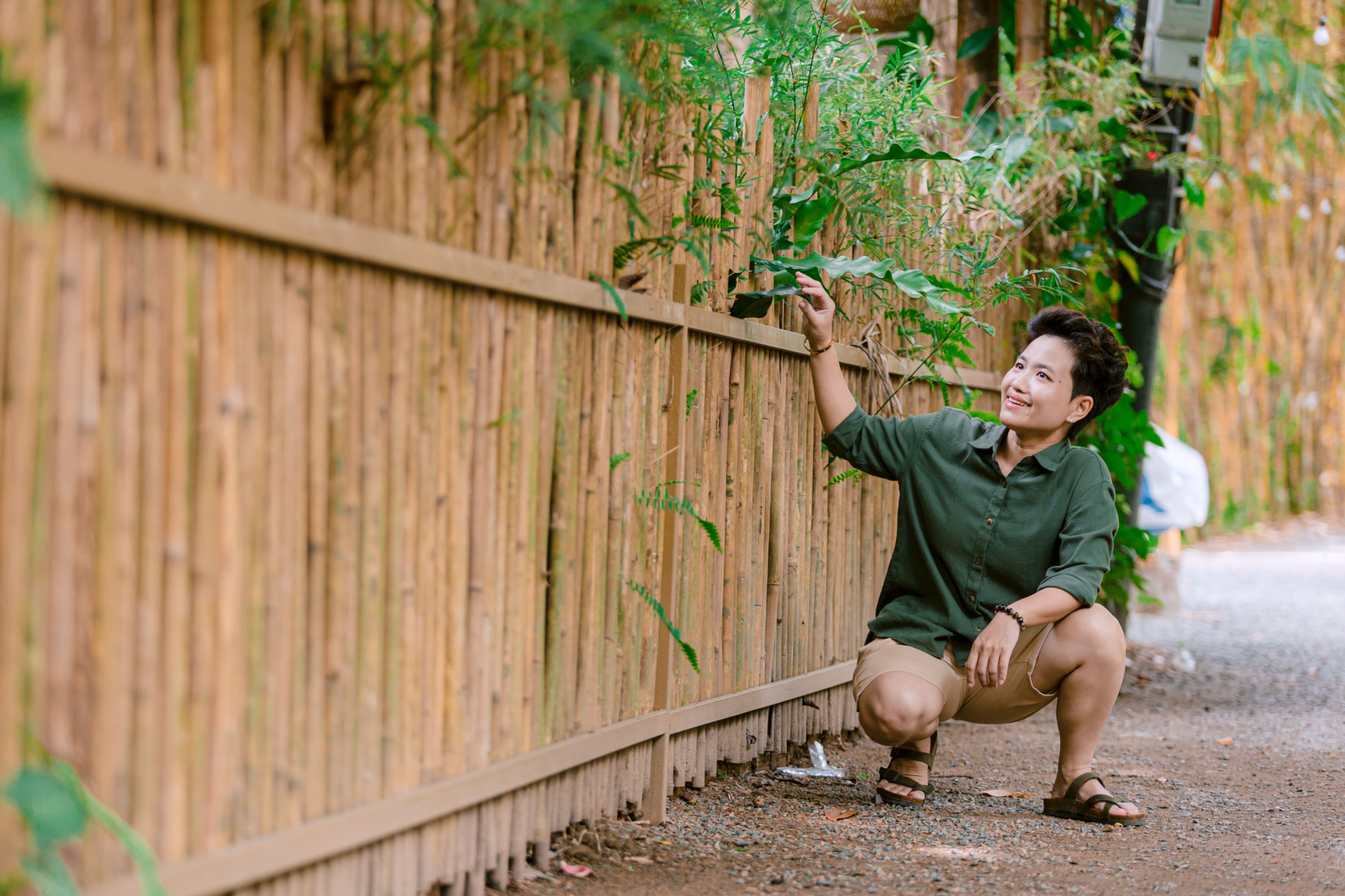 Smiling Person Enjoying Nature Walk Along Bamboo Fence · Free Stock Photo