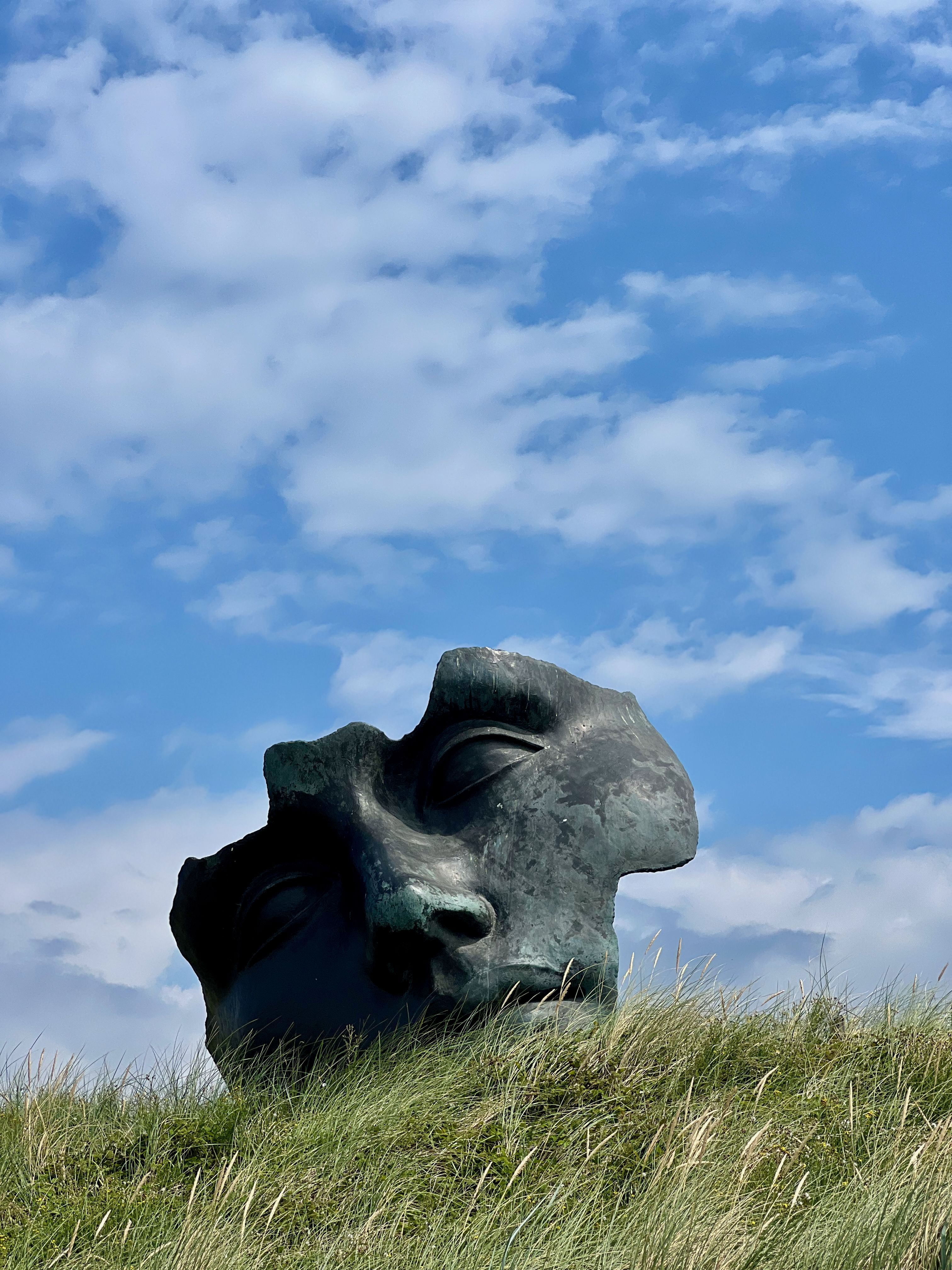 Sculptural Face Statue in Grass Field Under Blue Sky · Free Stock Photo