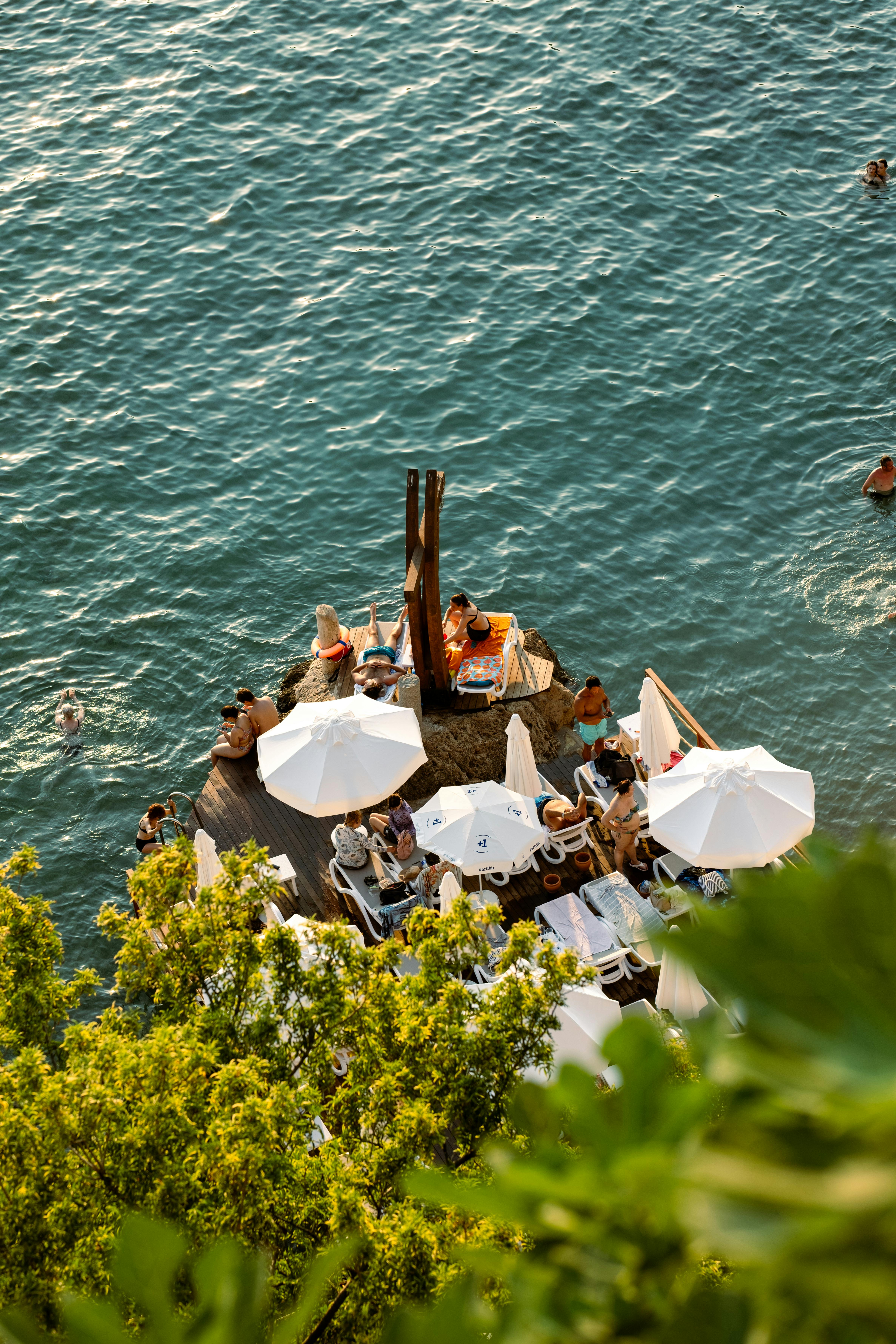 Relaxing Beachside Scene with Umbrellas and Swimmers · Free Stock Photo