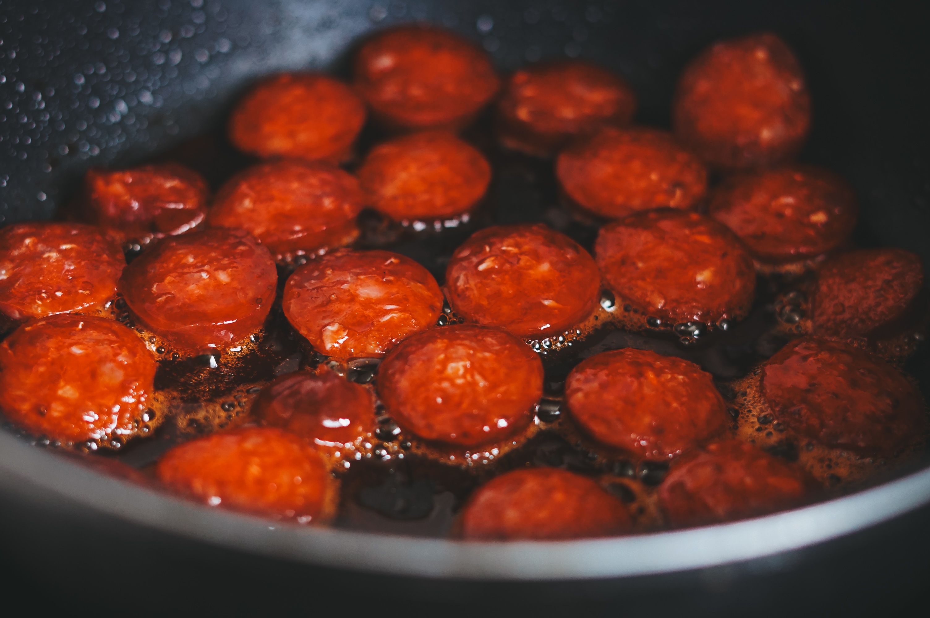 Frying Sliced Sausages in a Pan Close-Up · Free Stock Photo