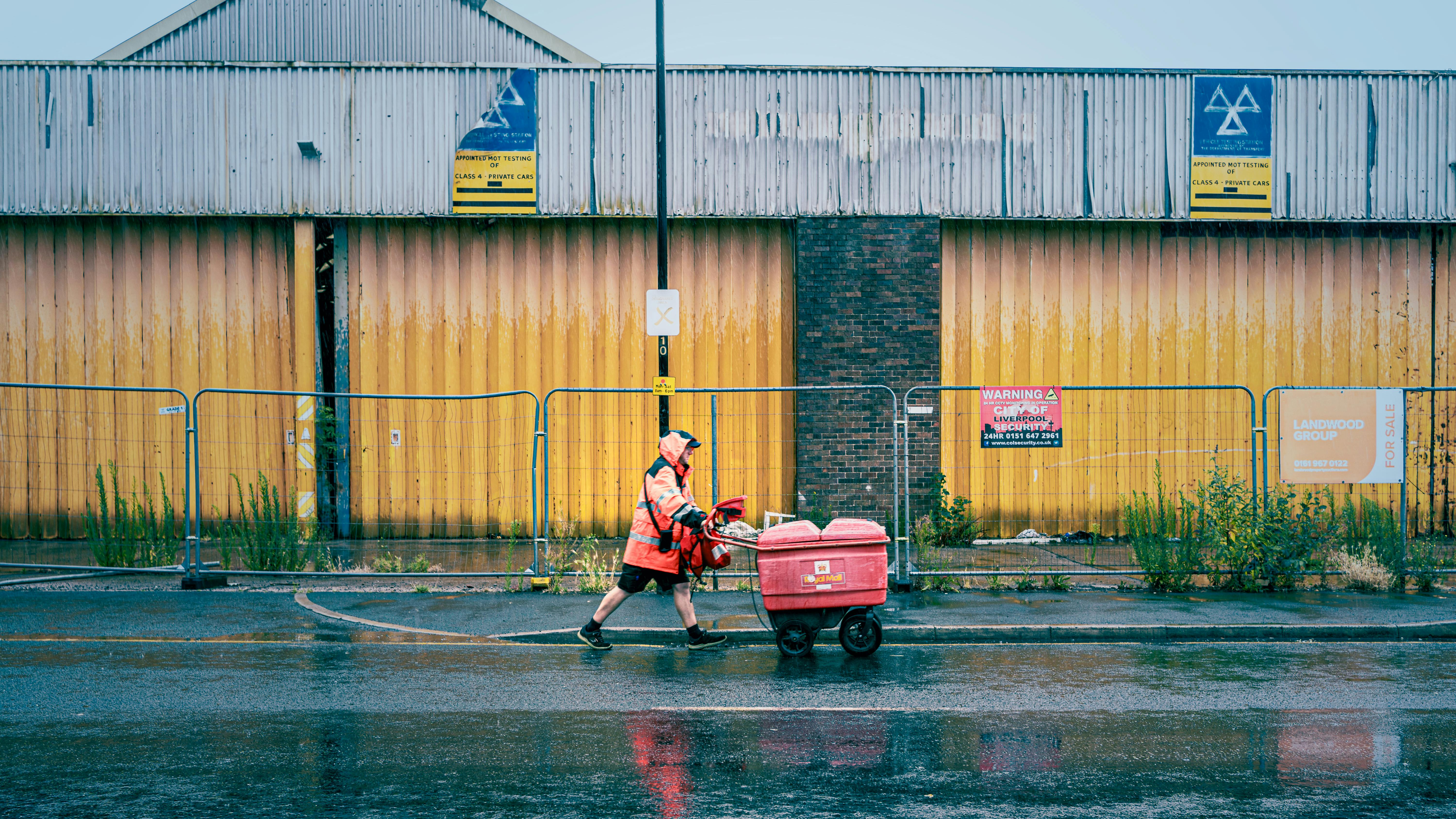 Cartero Caminando Bajo La Lluvia Junto A Un Edificio Industrial · Foto ...