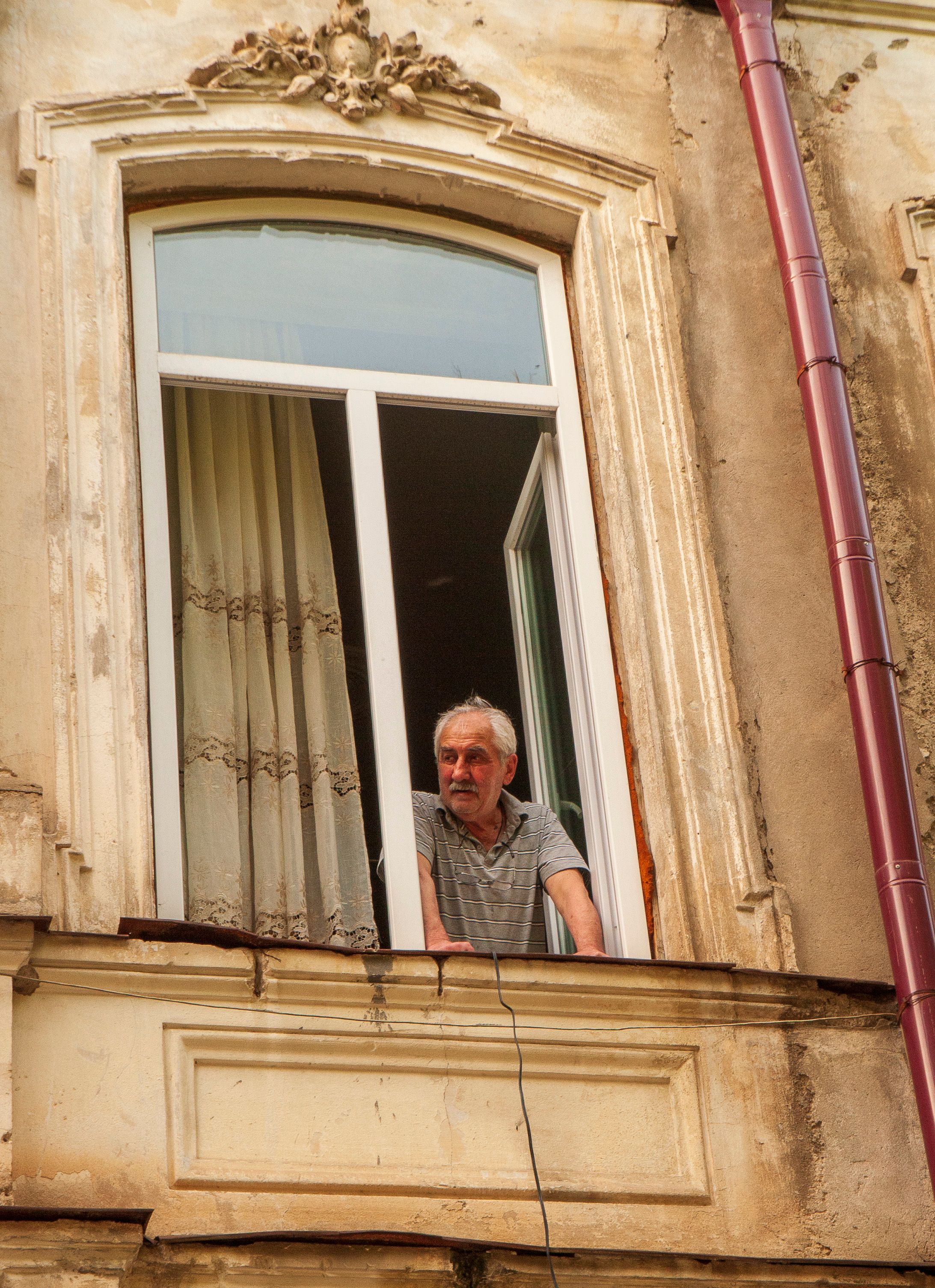 Elderly Man Looking Out Sculpted Window · Free Stock Photo