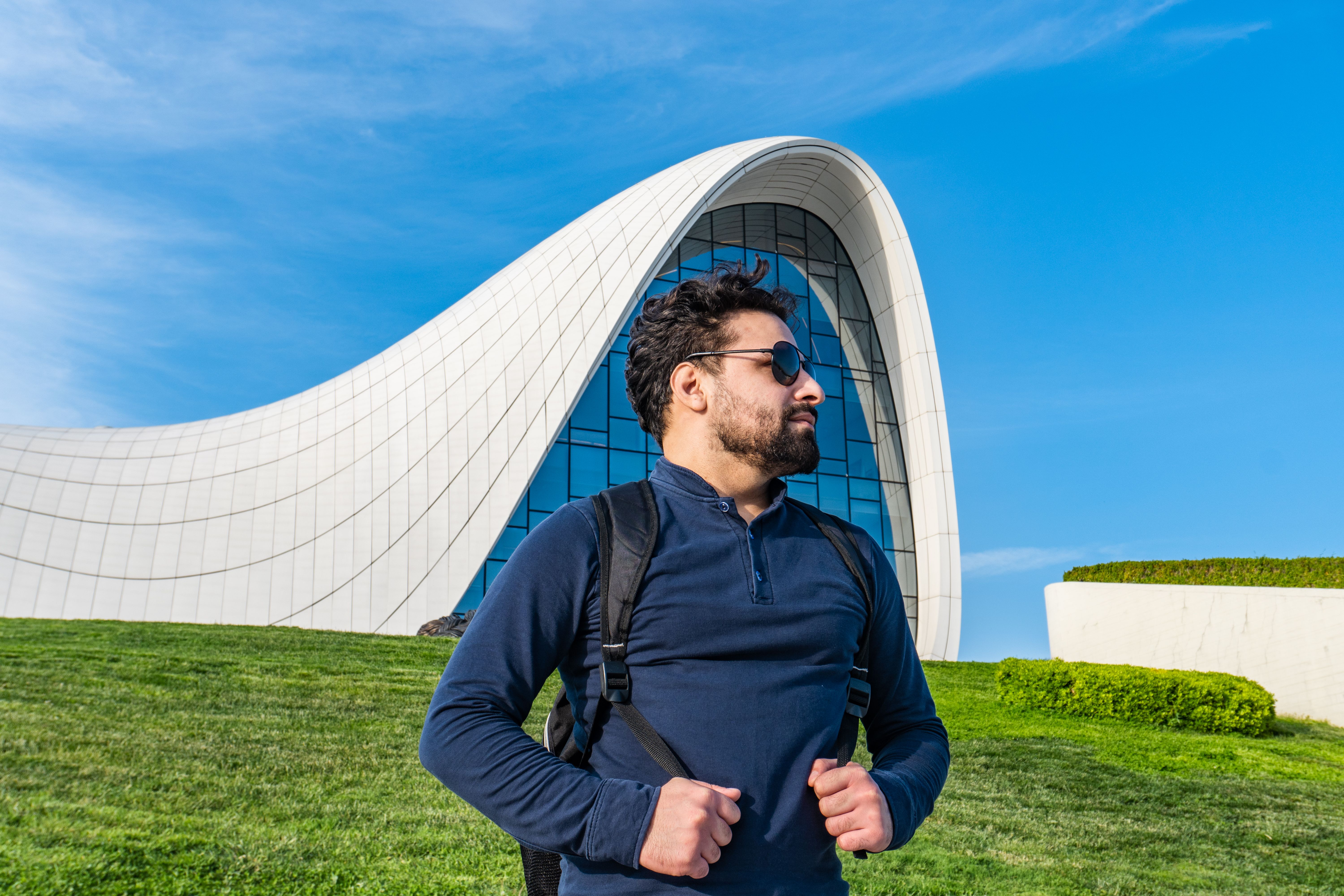 A Man with Backpack in Front of Modern Architecture · Free Stock Photo