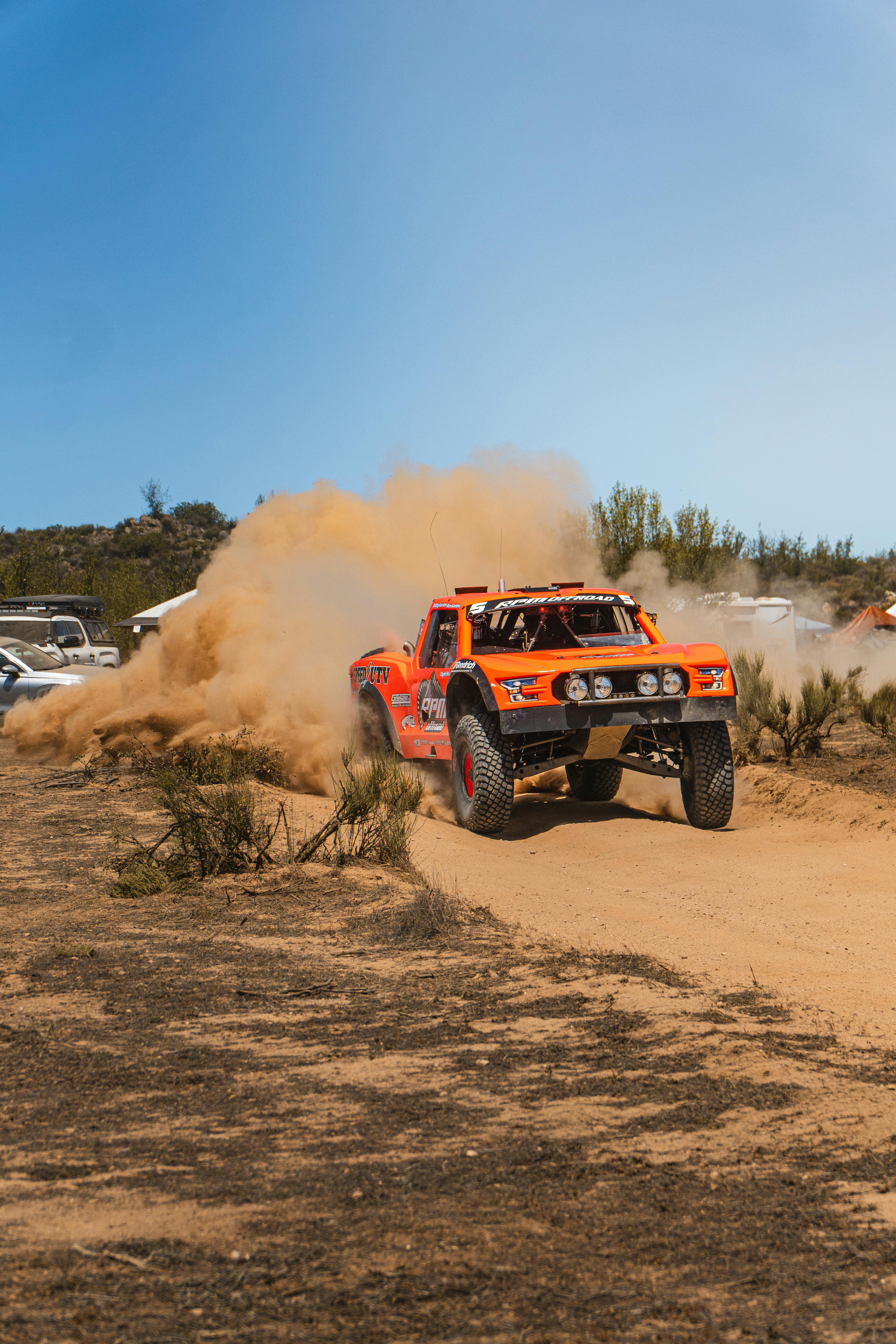 Orange Off-Road Vehicle Racing in Dusty Landscape · Free Stock Photo