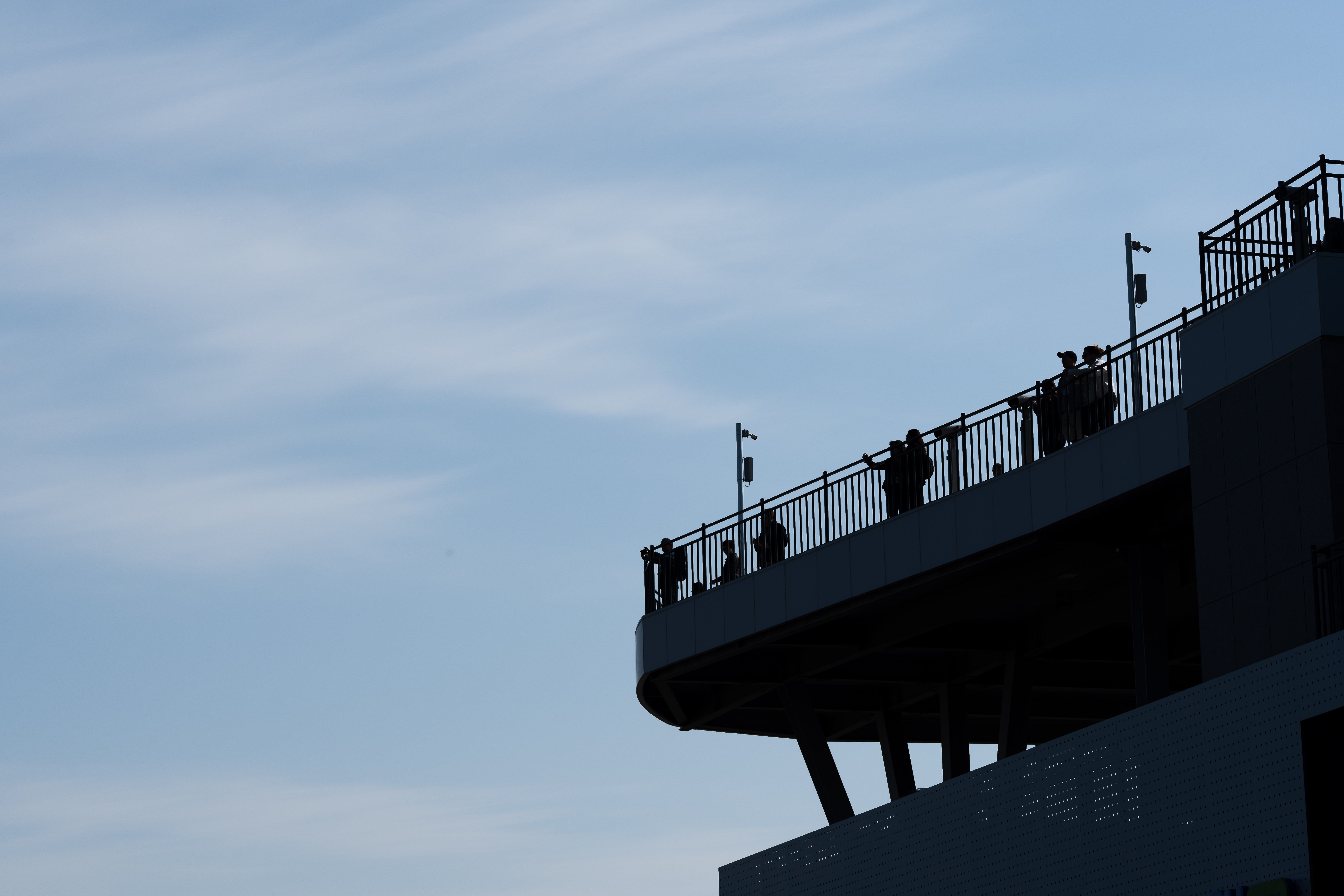 Silhouetted Figures on Rooftop Against Blue Sky · Free Stock Photo